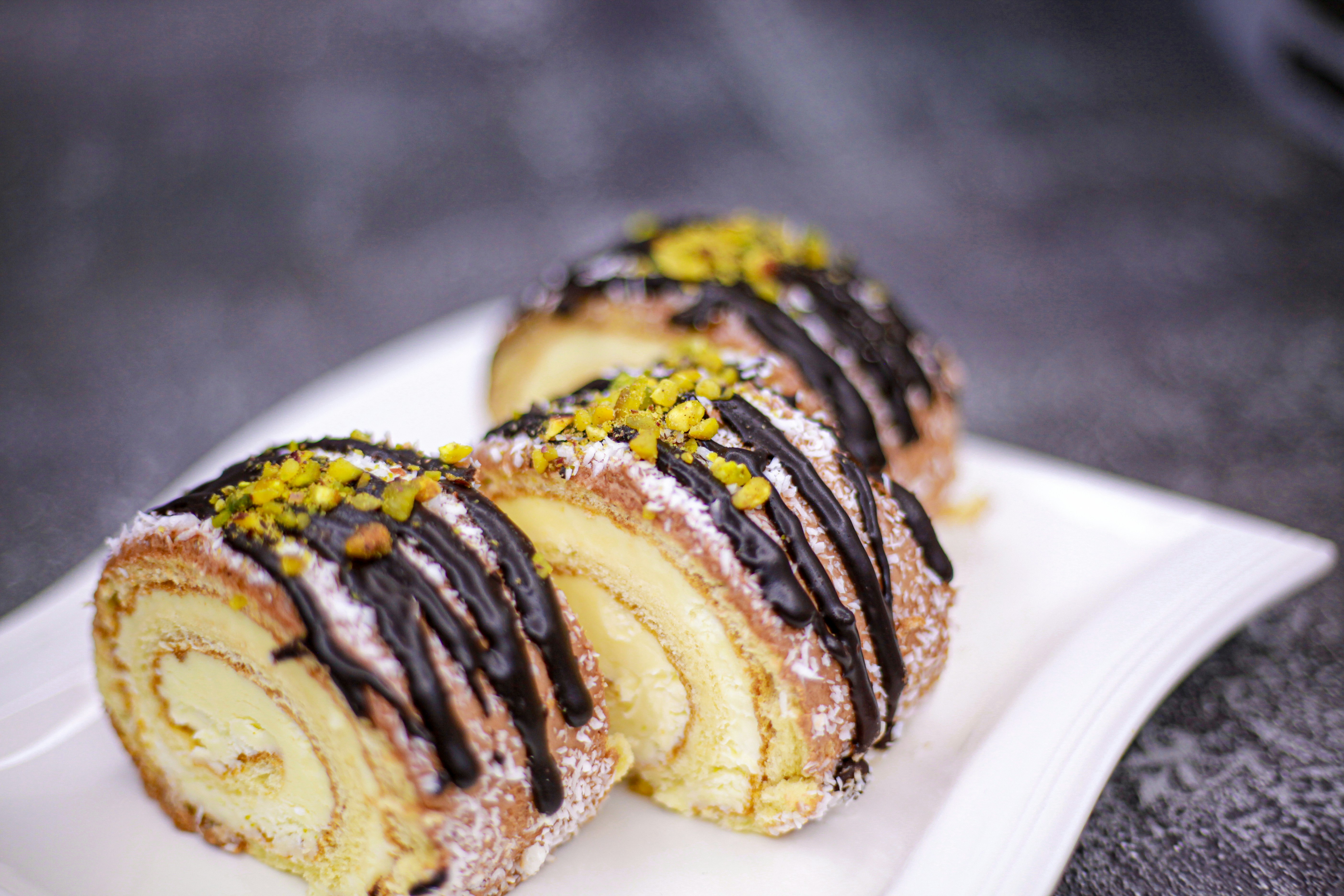 Rolls of Sweetness: Chocolate Drizzle and Pistachio Garnish