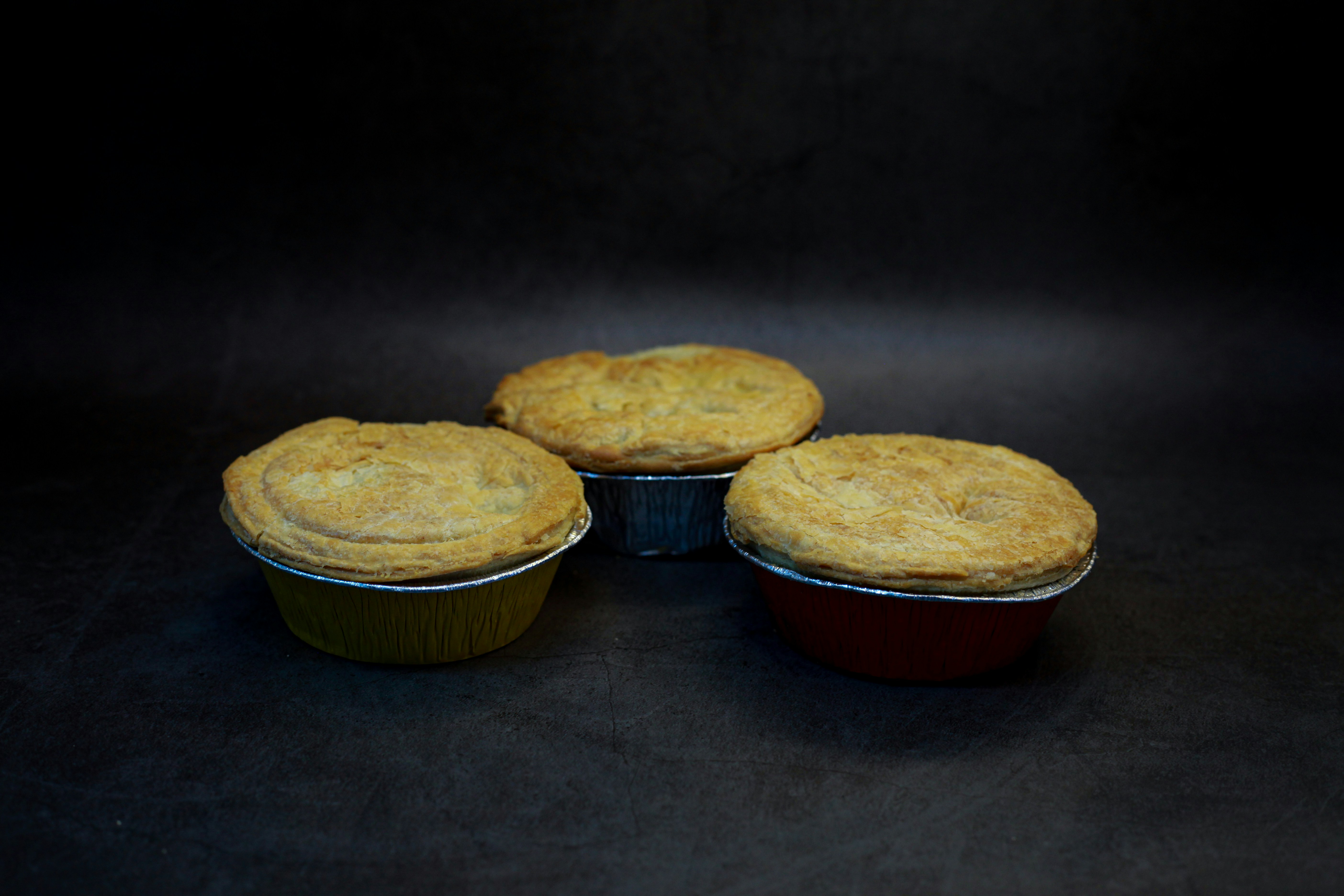 Triad of Golden Pies on a Quiet Studio Stage