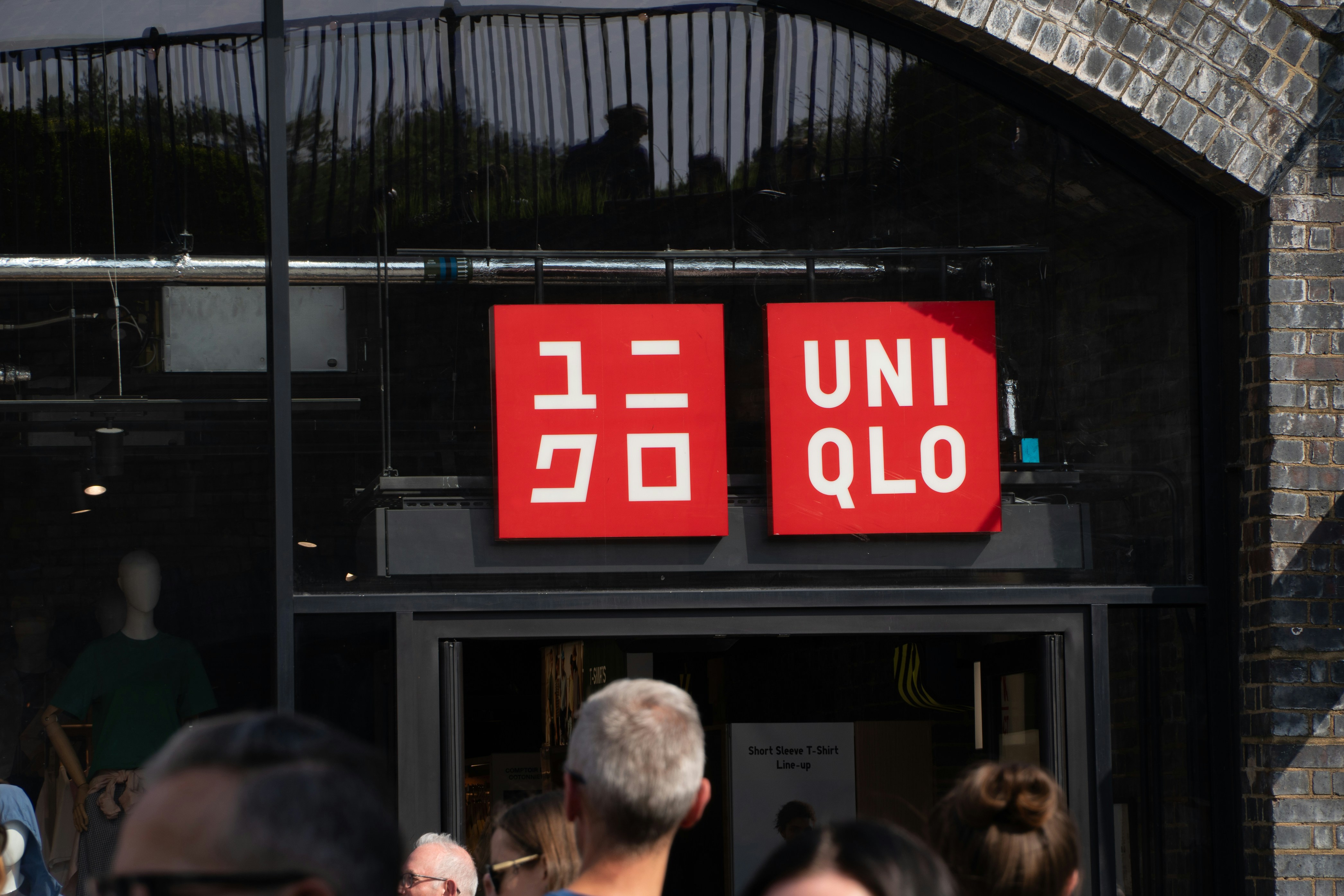 Uniqlo at the Threshold: Red Sign, Dark Arch, and Crowded Entrance