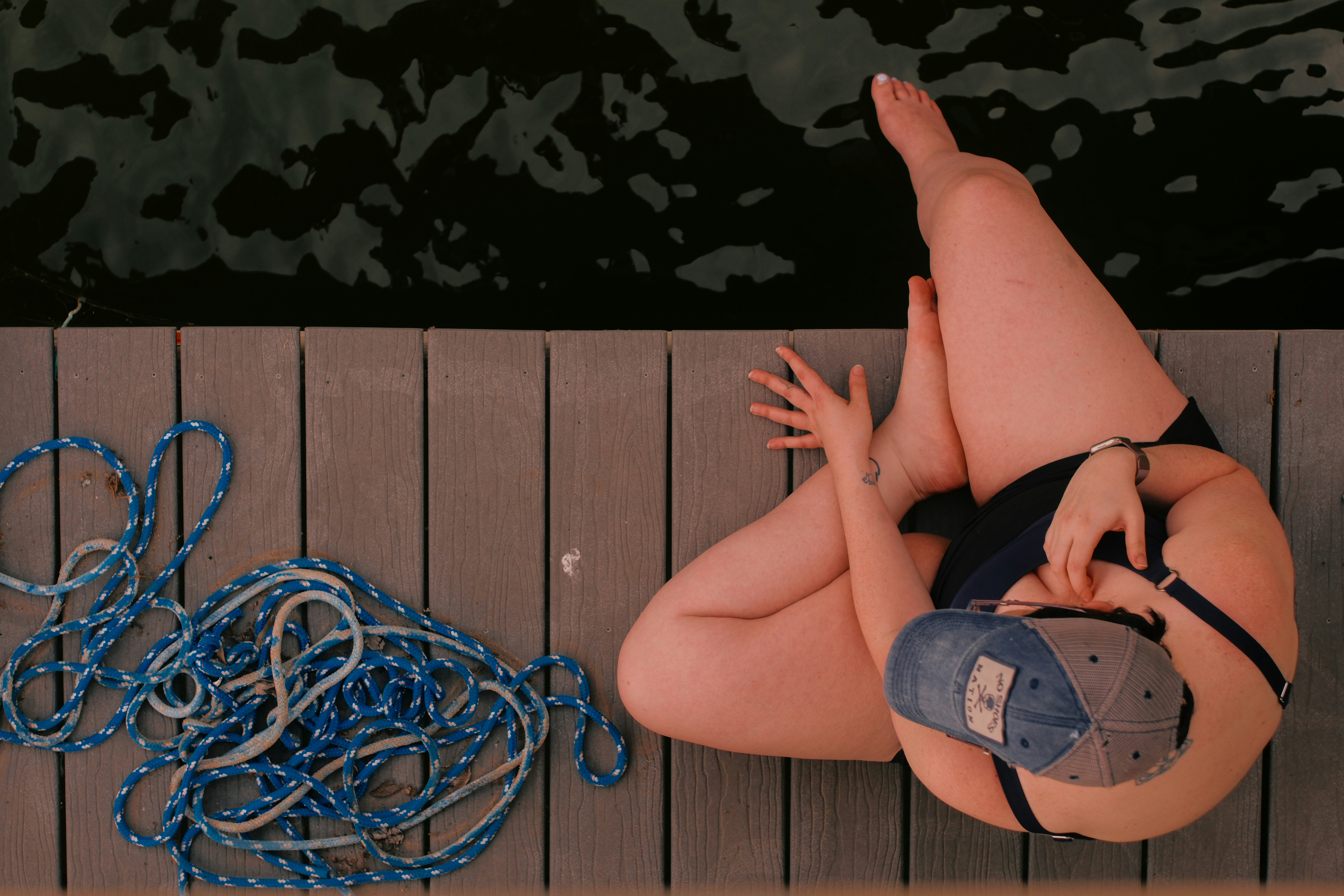 A sunlit deck dive: swimmer poised at the edge with a rope companion