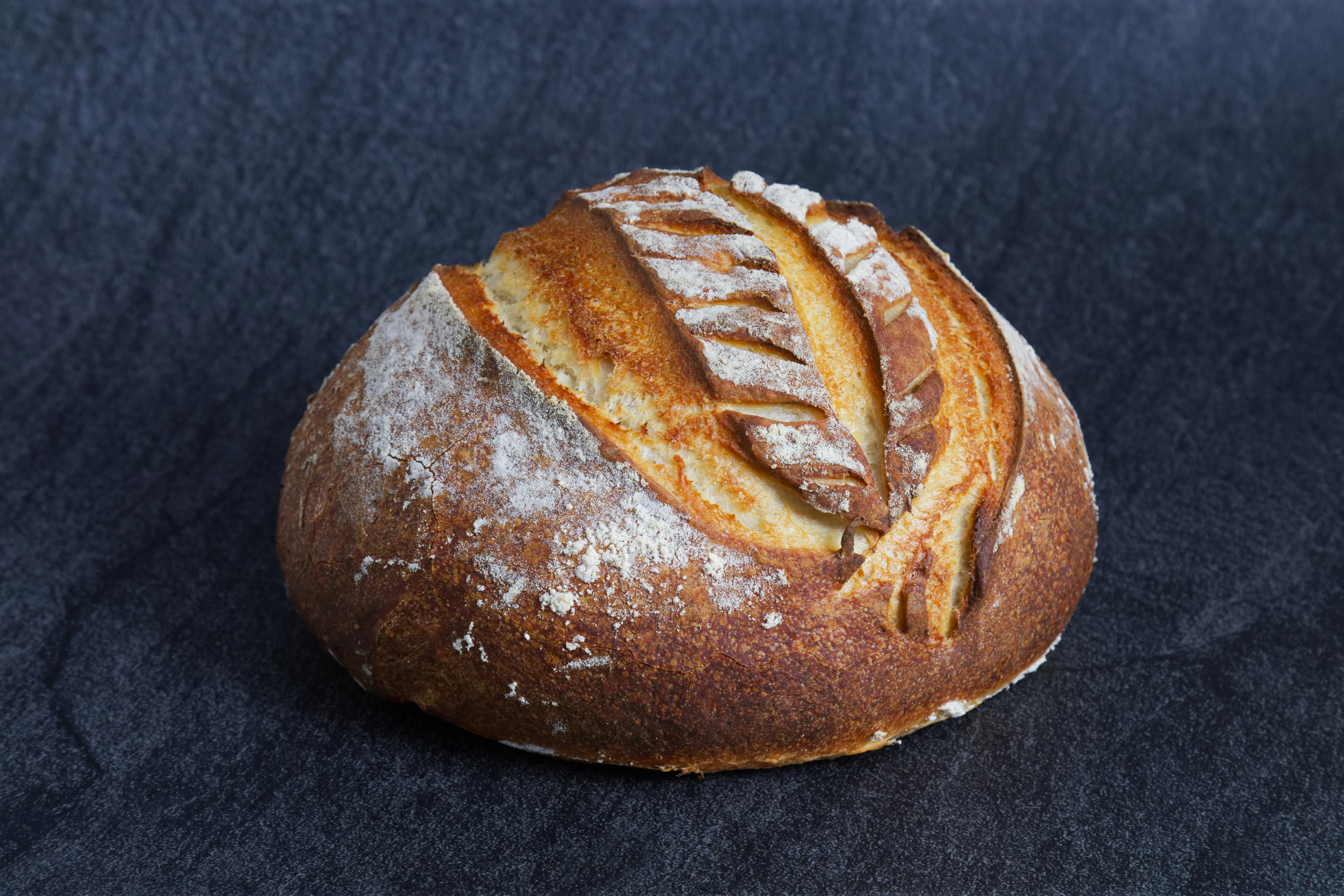 A rustic loaf resting on midnight fabric, dusted with flour