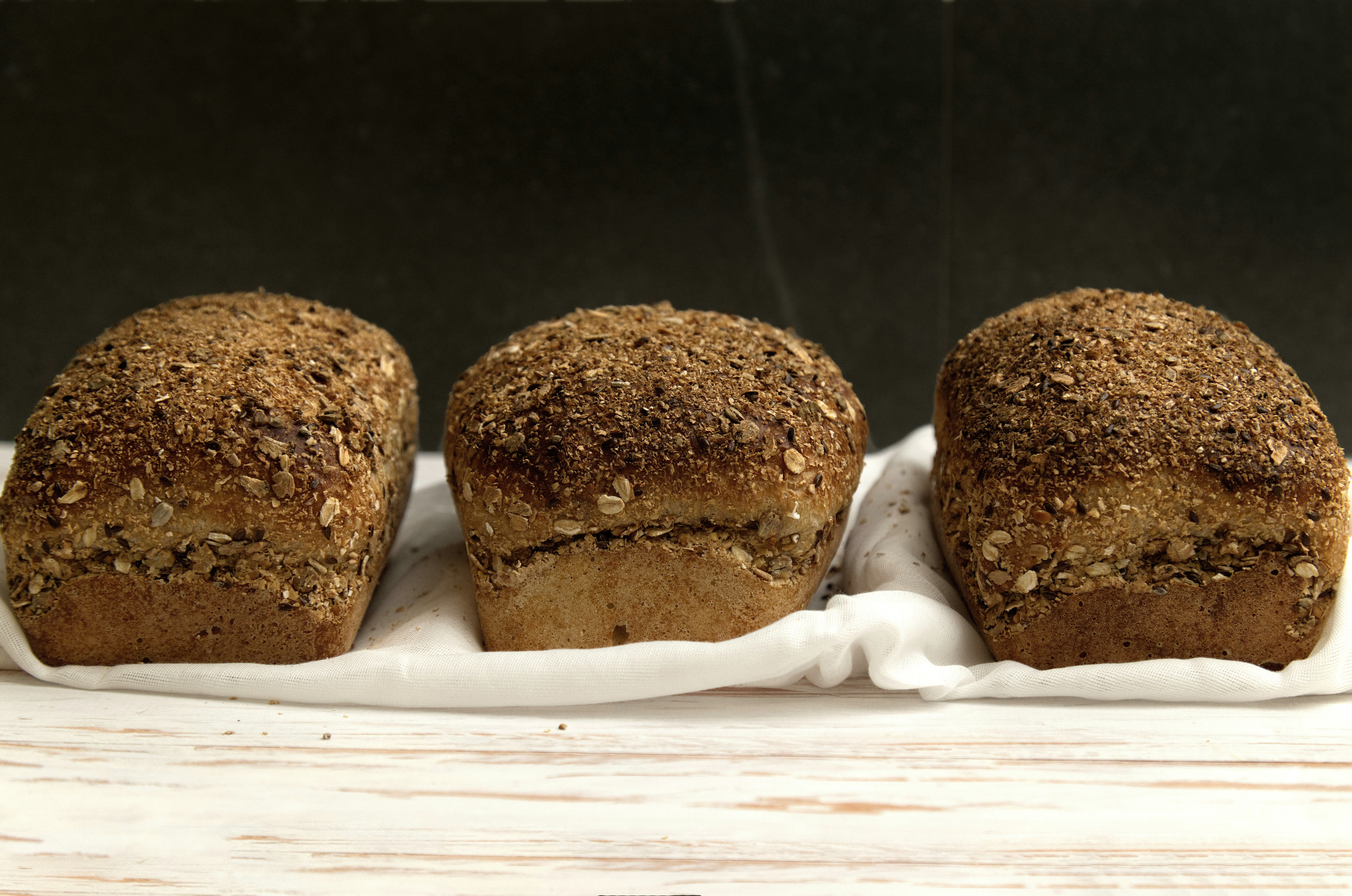 Three Seeded Buns Resting on a White Cloth Mat