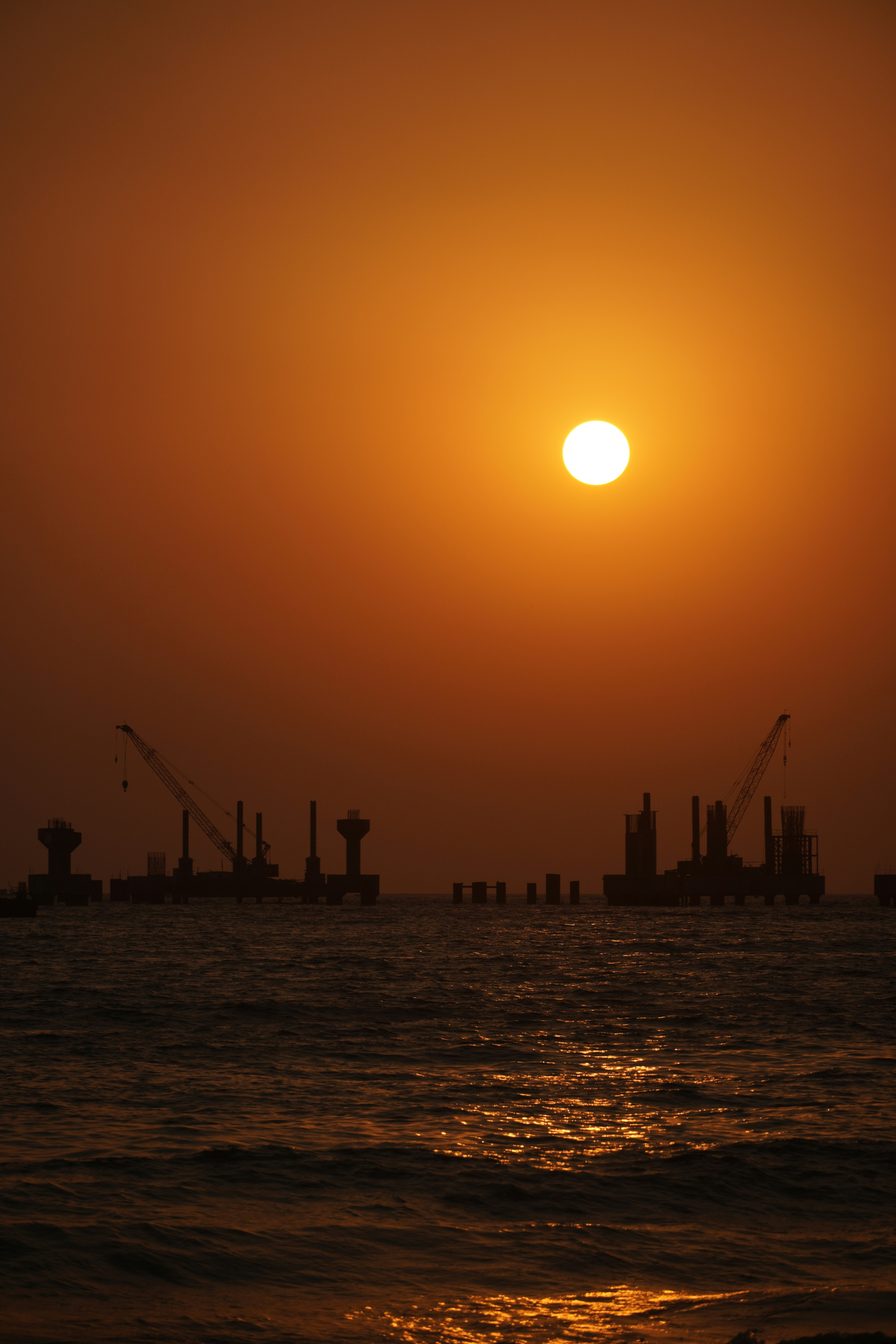 Sunlit silhouettes: Offshore cranes against a velvet sunset