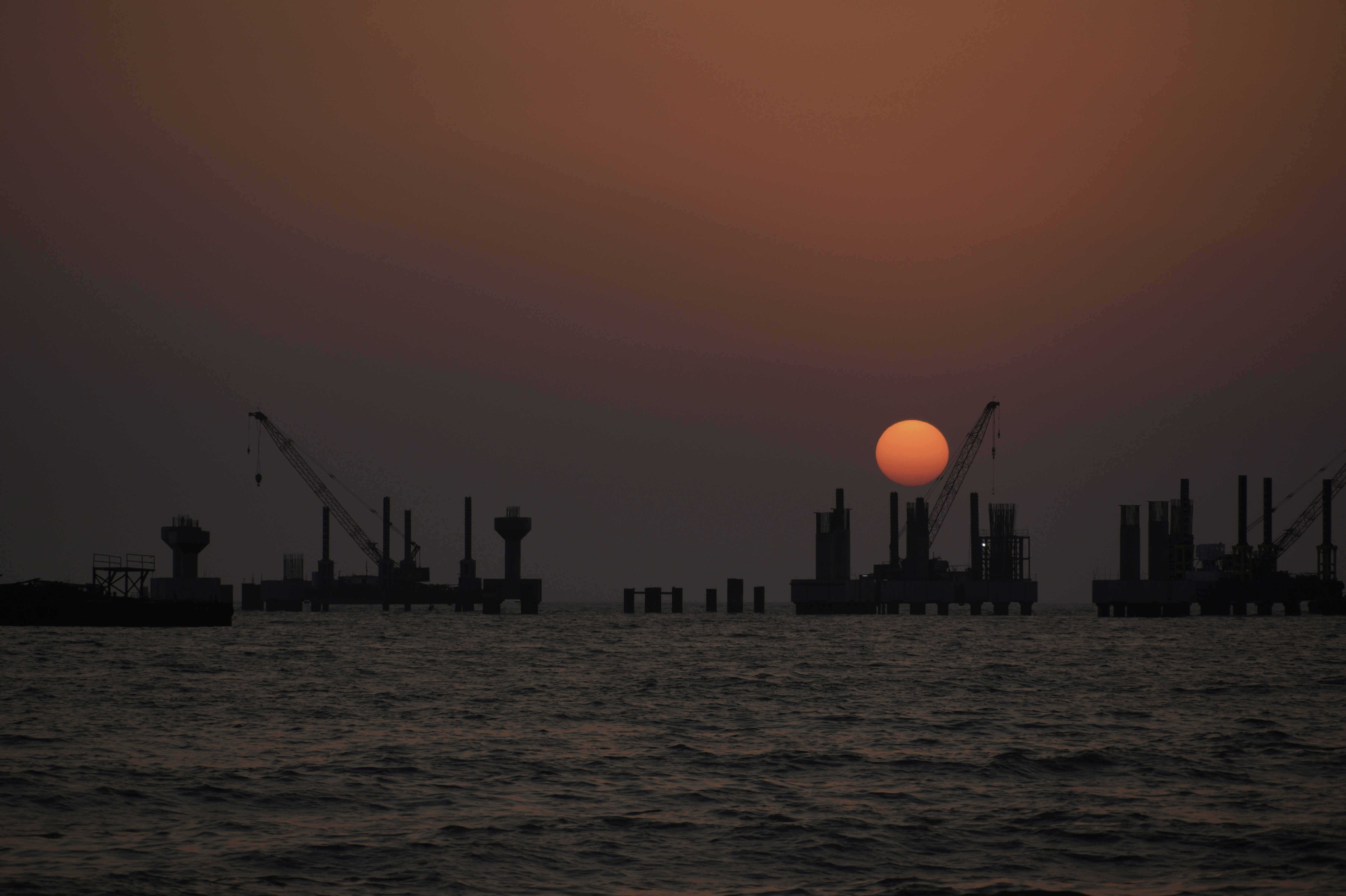 Sunset Rig: Dusk Over a Harbor with Silhouetted Cranes