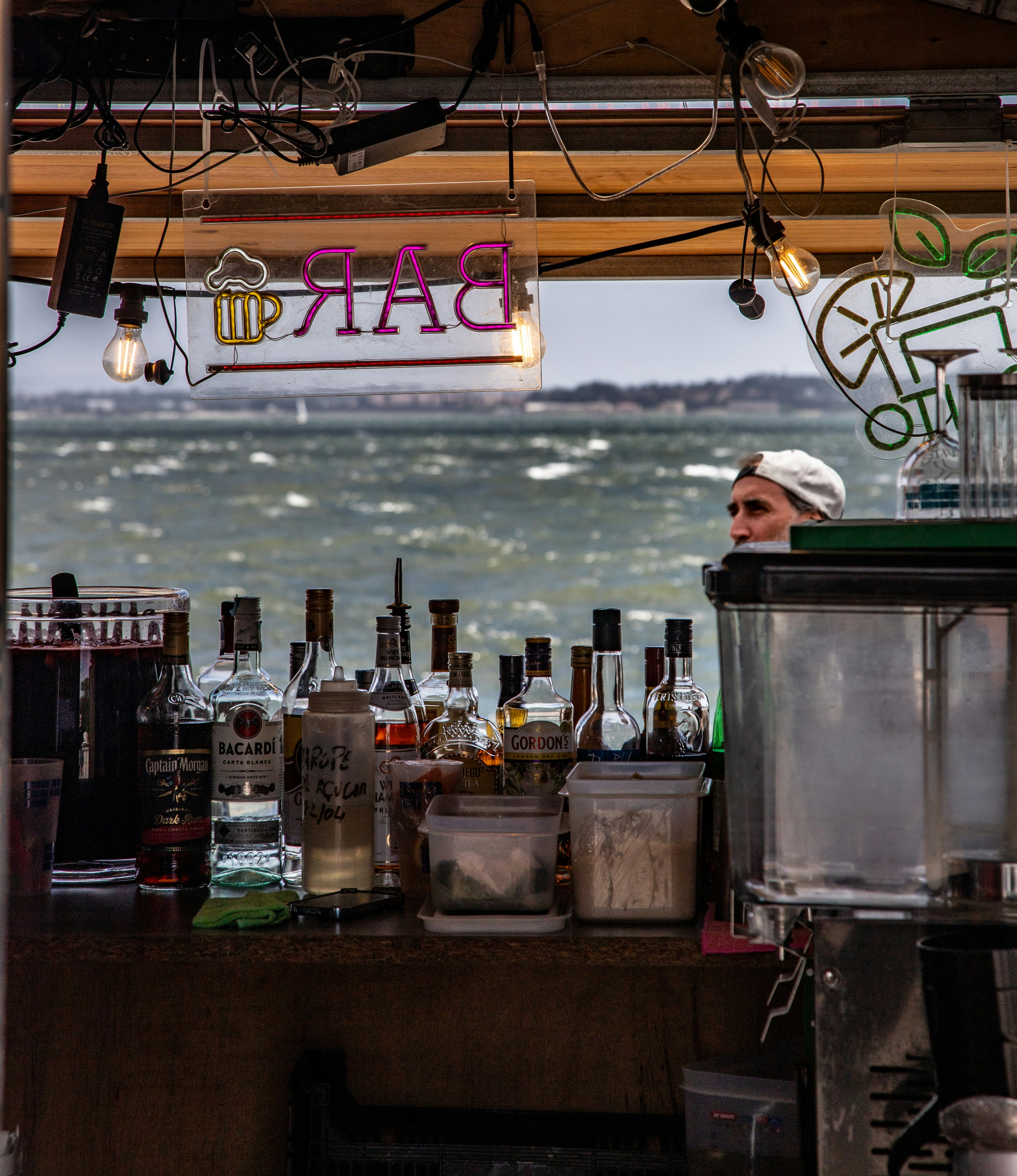 Harbor Bar at Dusk: Bottles, Ocean Vista, and a Watchful Bartender