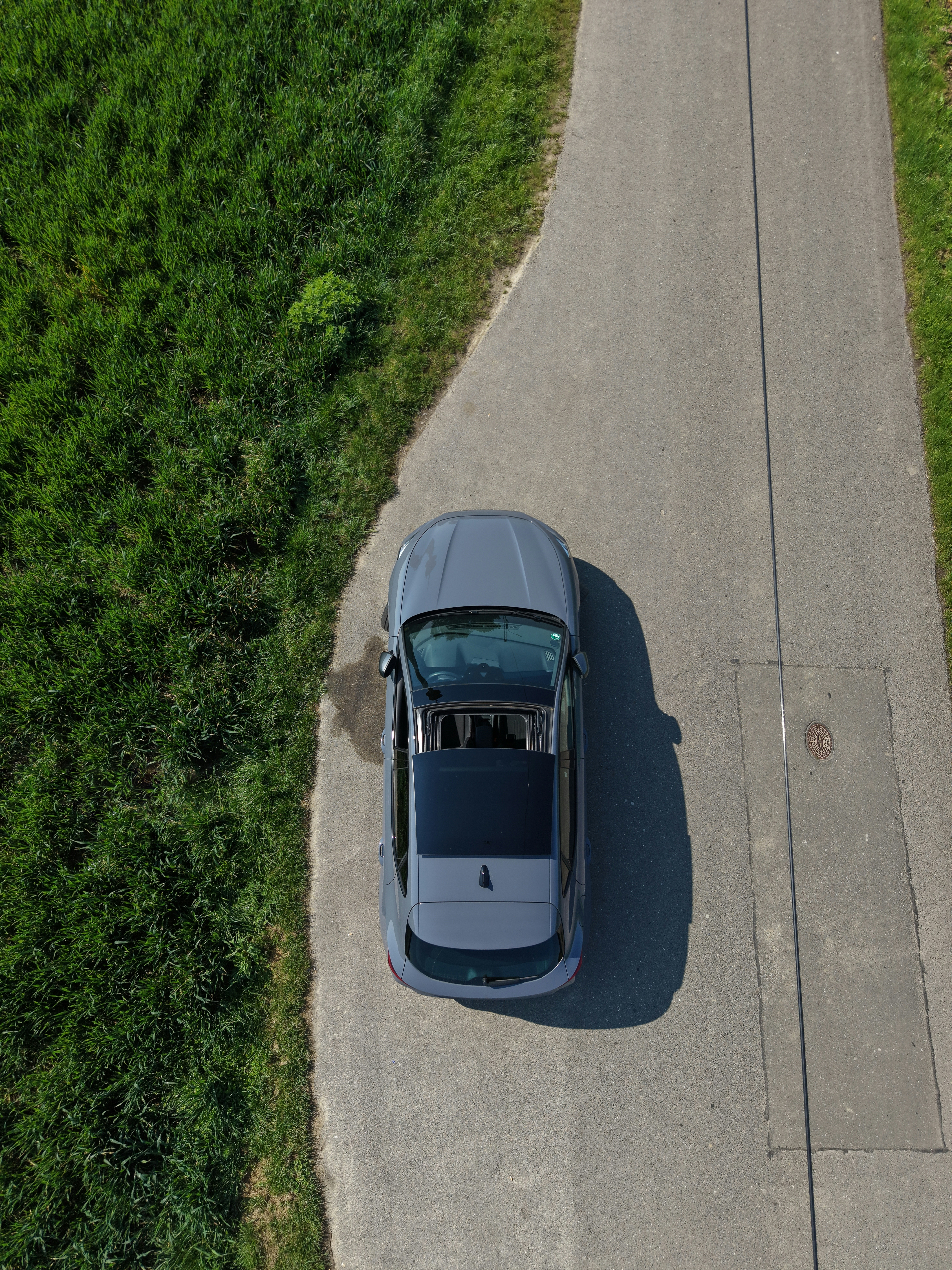 Aerial Transit: Silver sedan on a country road bordered by green verge
