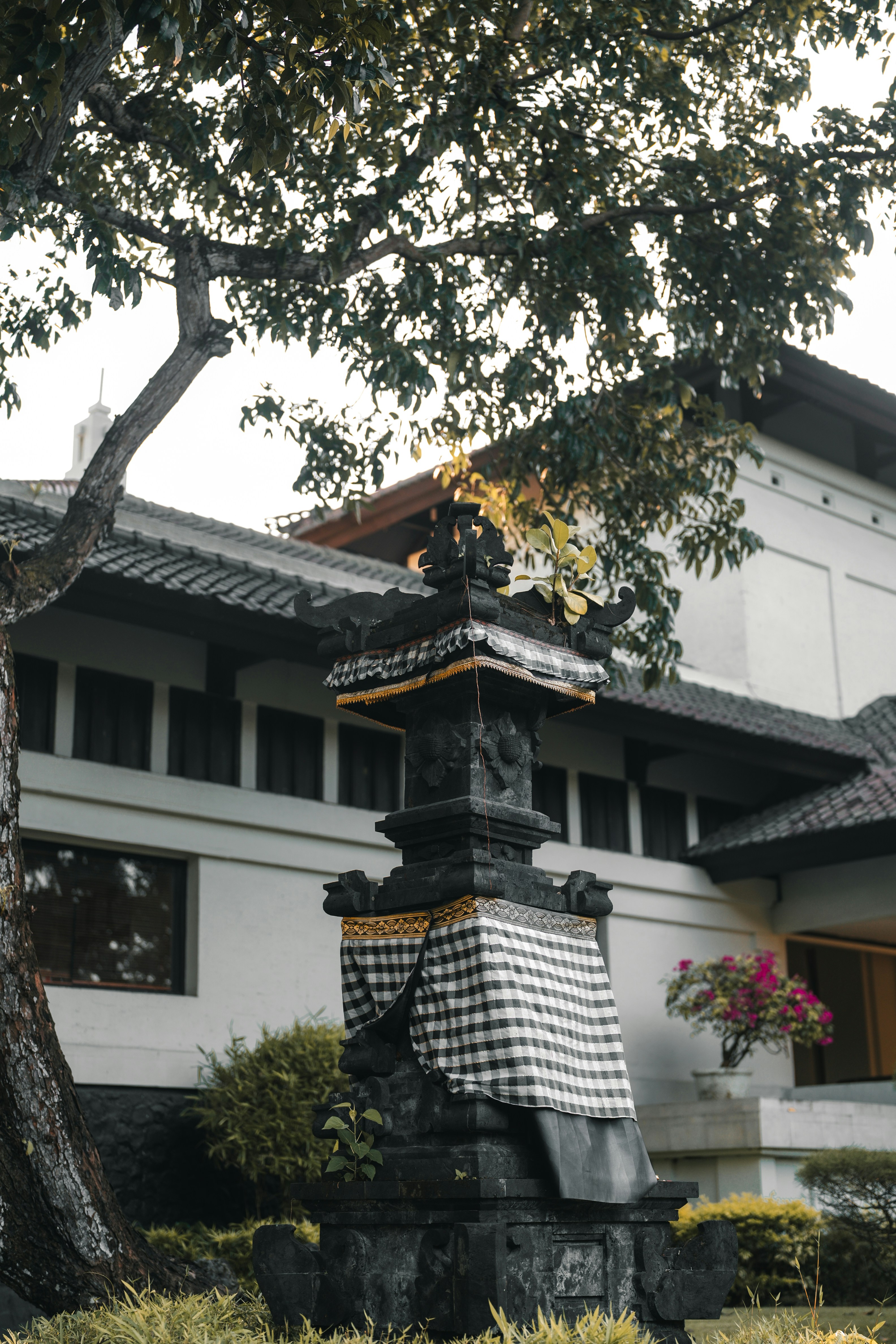 Stone shrine with striped cloth under a leafy canopy