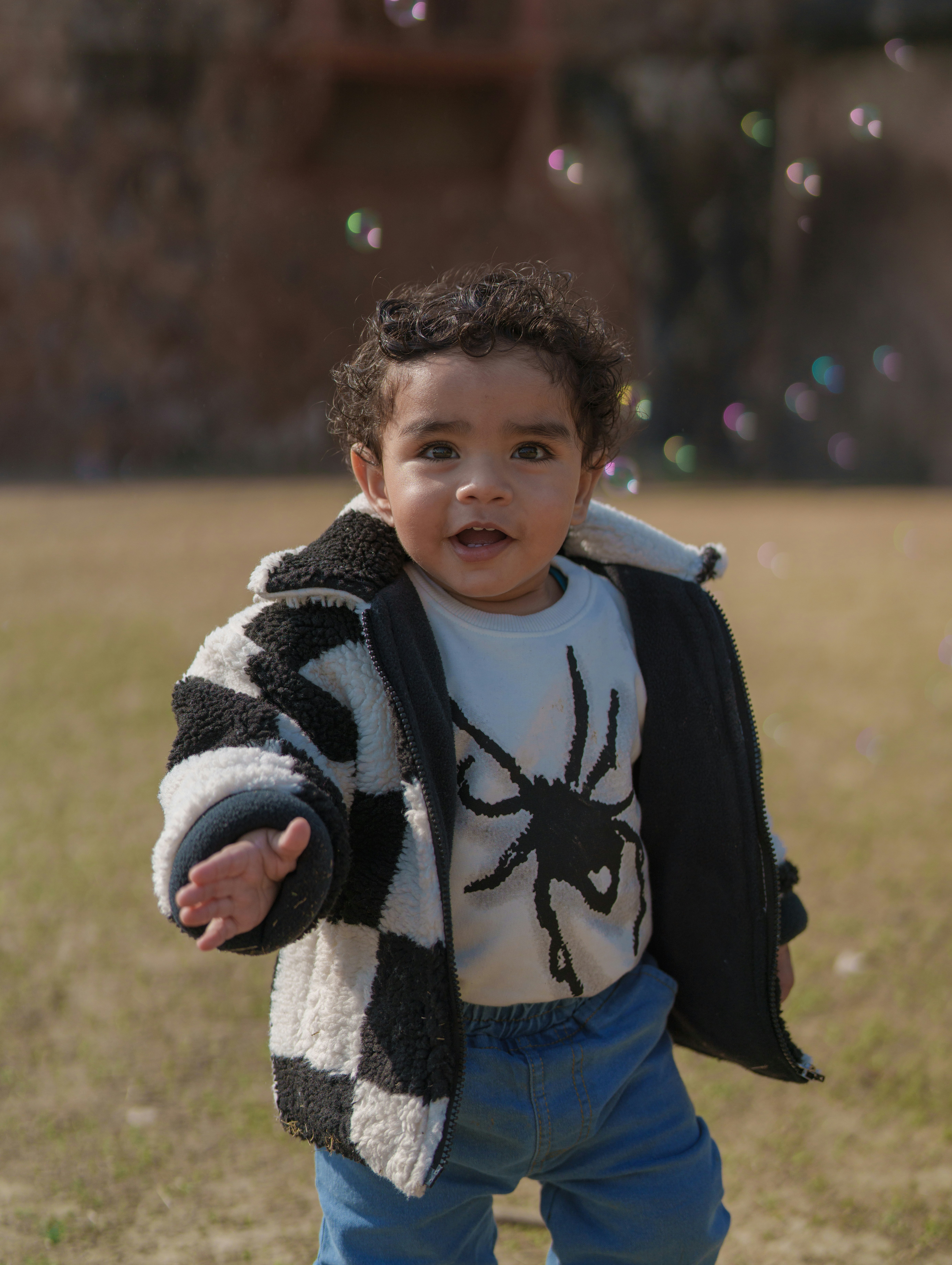 Child Reaches Toward Bubbles in a Sunlit Park