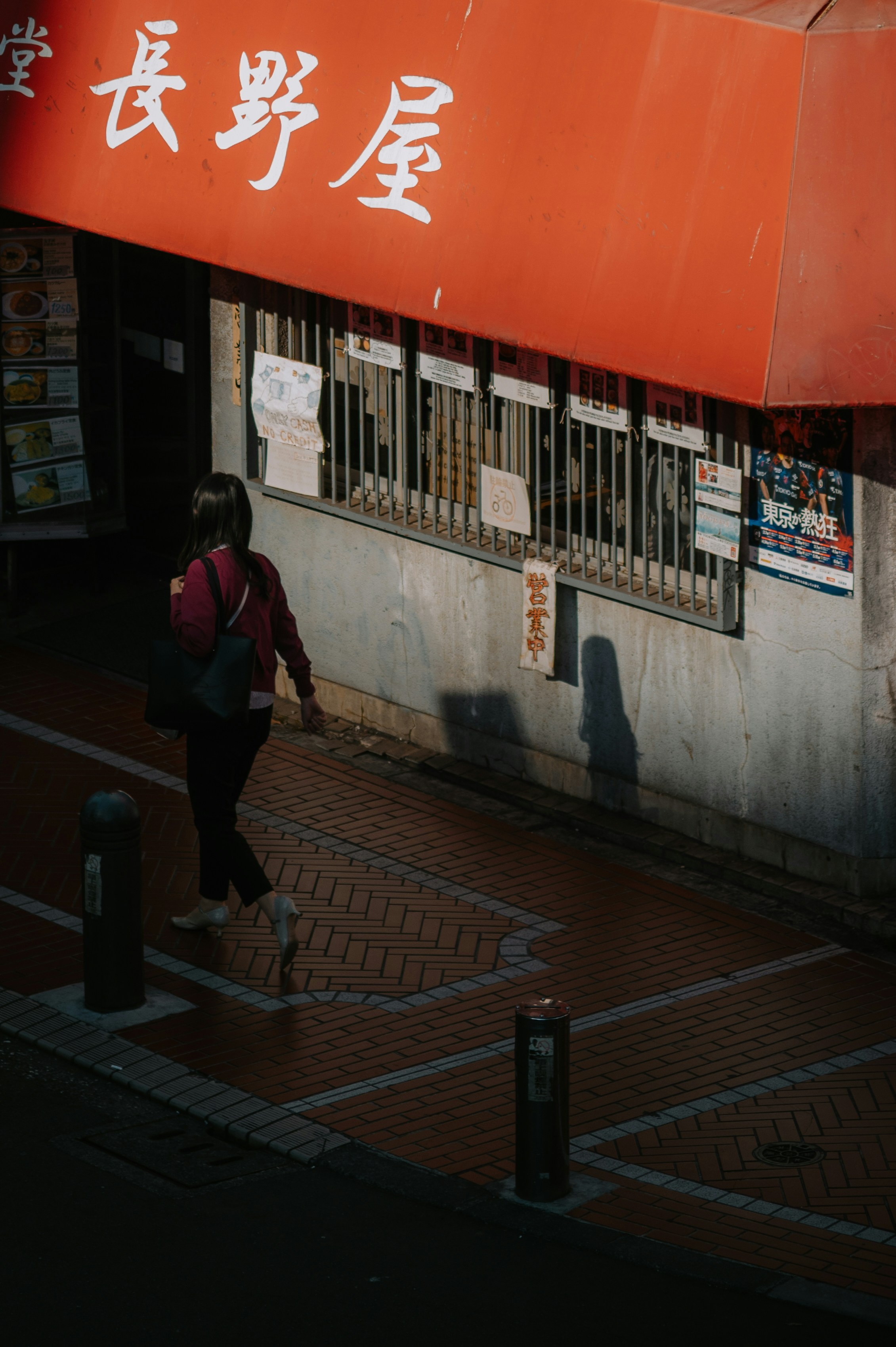 Shadowed Pedestrian Beneath the Red Canopy