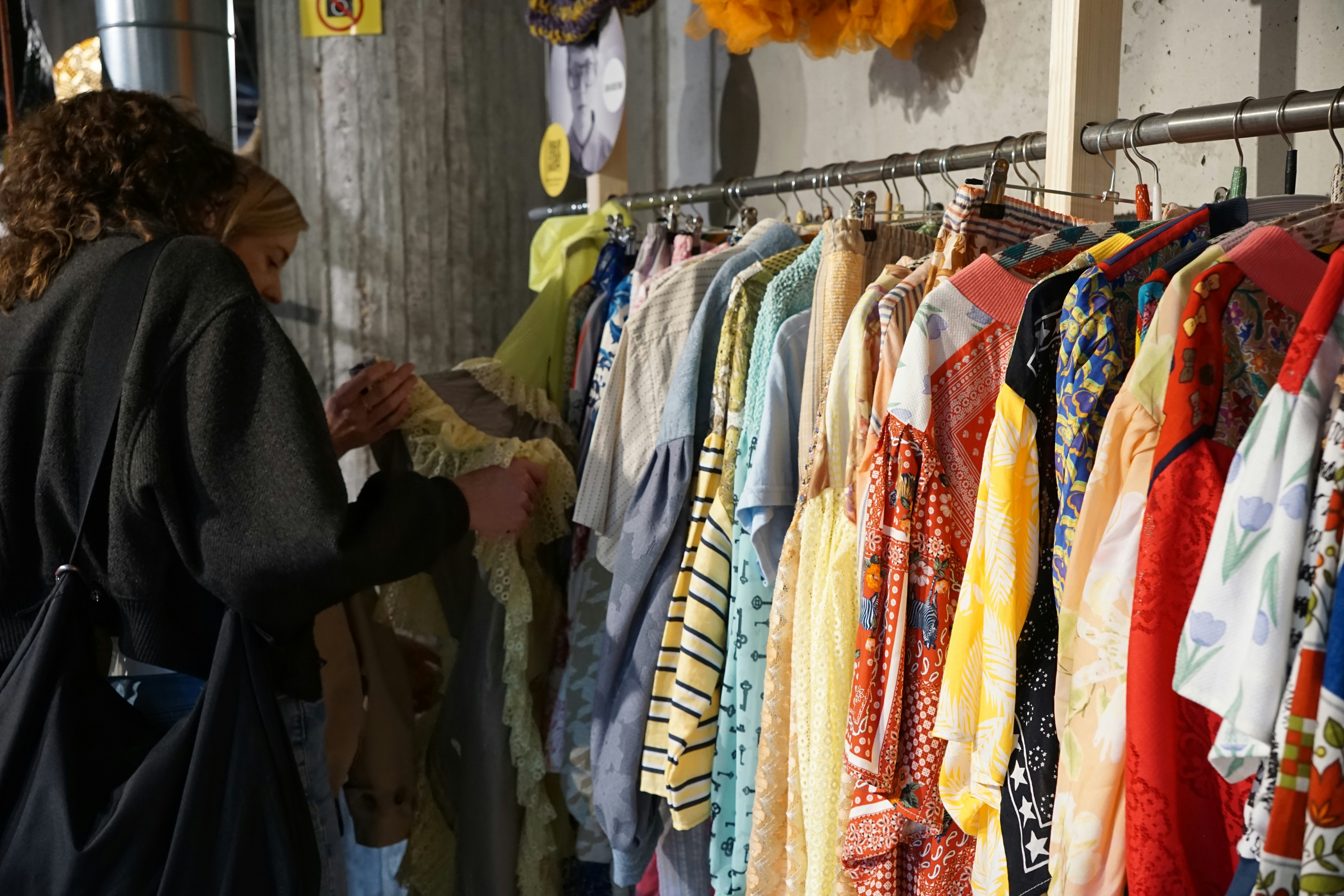 Clothes Rack Conversation: A shopper examines pieces in a vibrant boutique corner