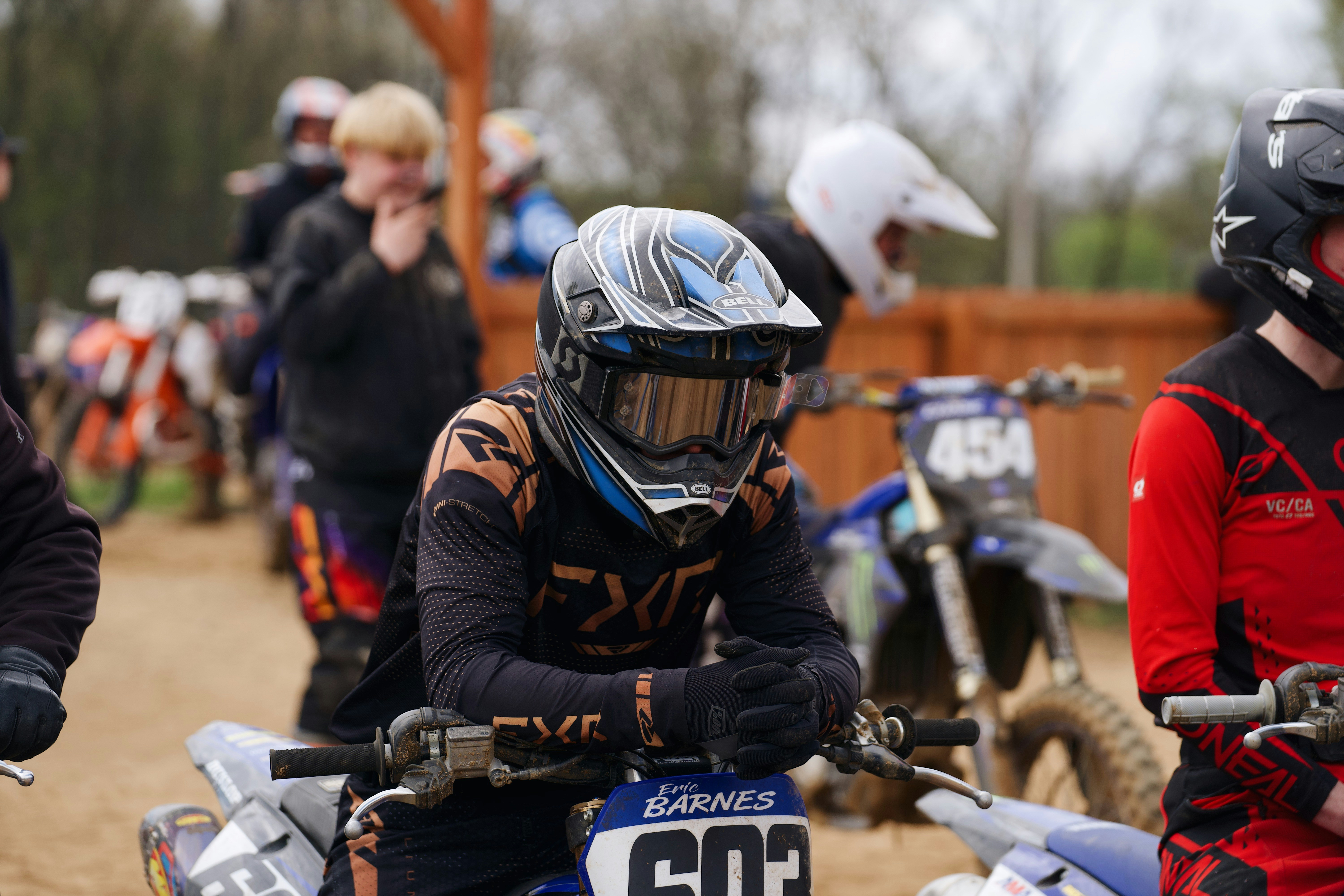 Blue-helmeted Rider Prepares for the Line as Muddy Track Buzzes with Activity