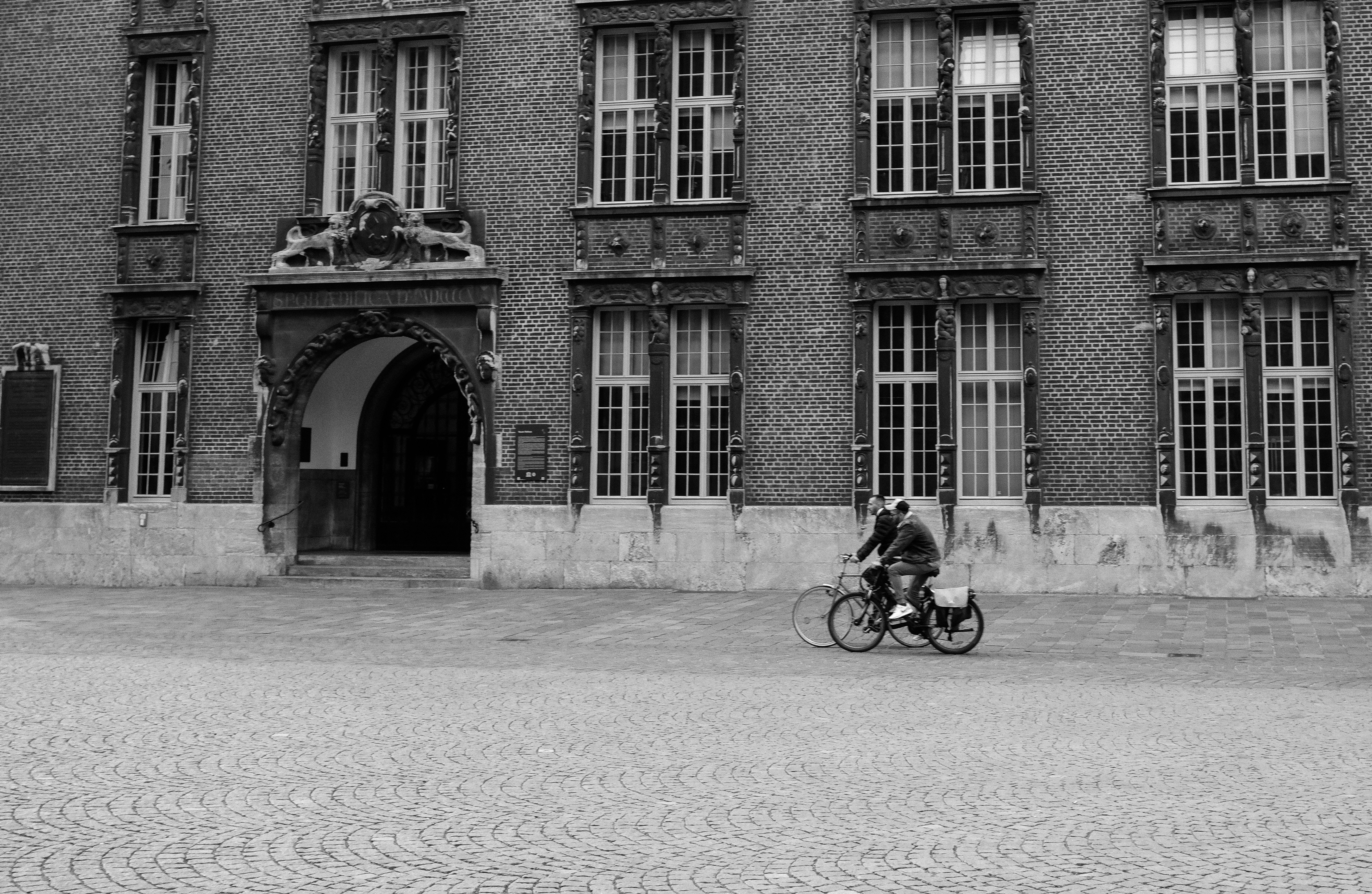 Cyclist Crossing the Facade: A Quiet Moment by the Old Brick Campus