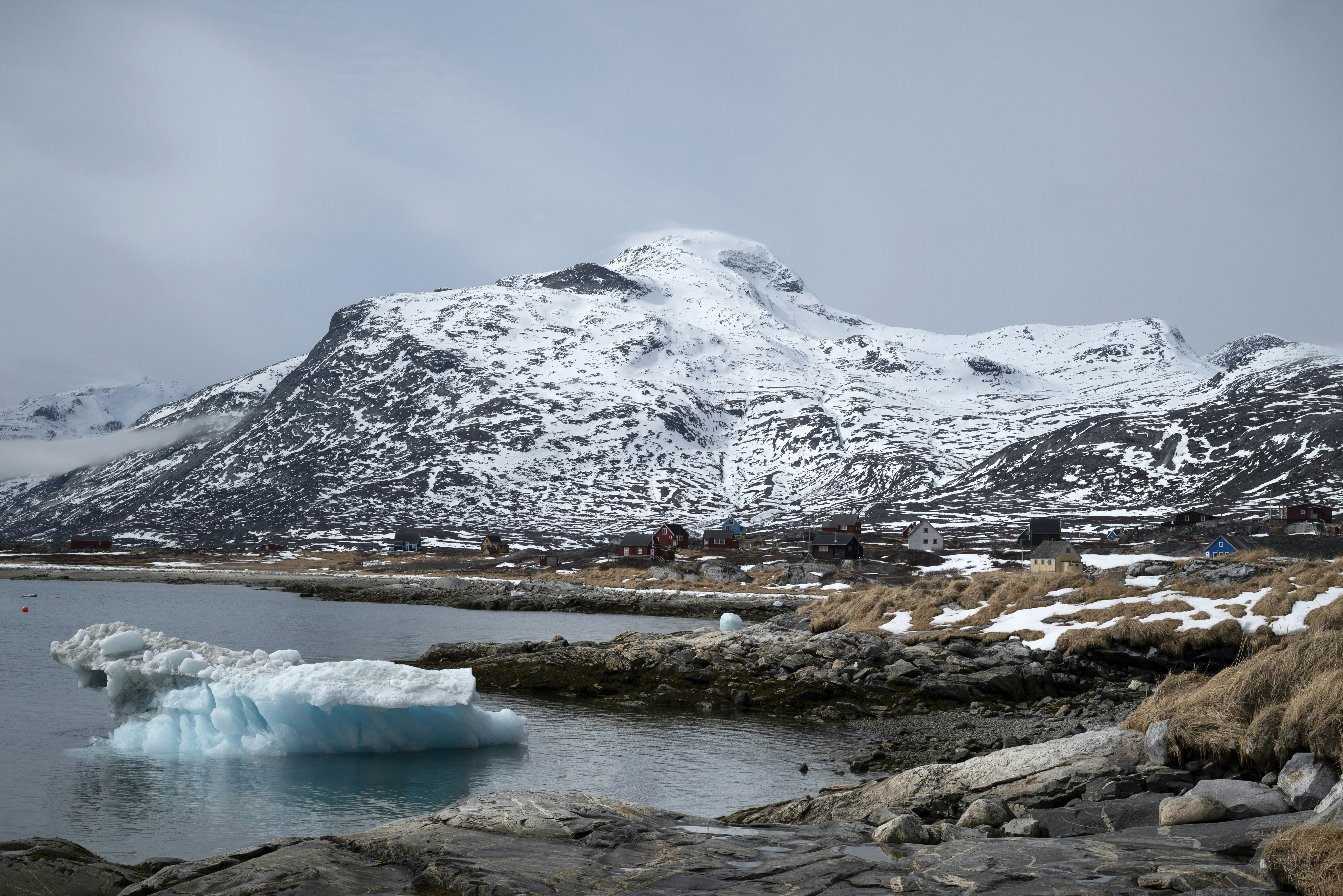 Snow-dusted pyramid peaks over a rugged fjord village