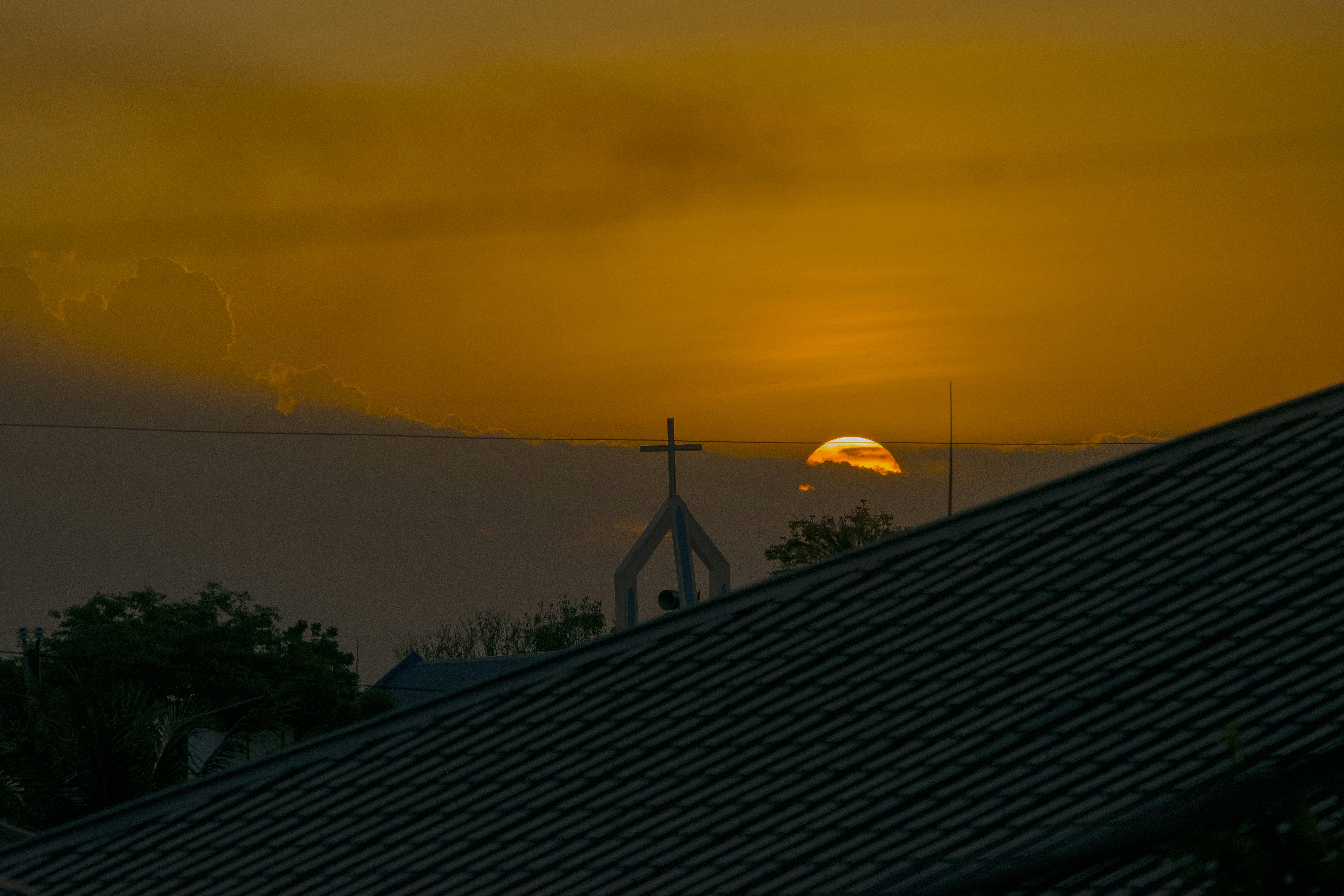 Sunset Silhouette over a Sloped Roof and Cross