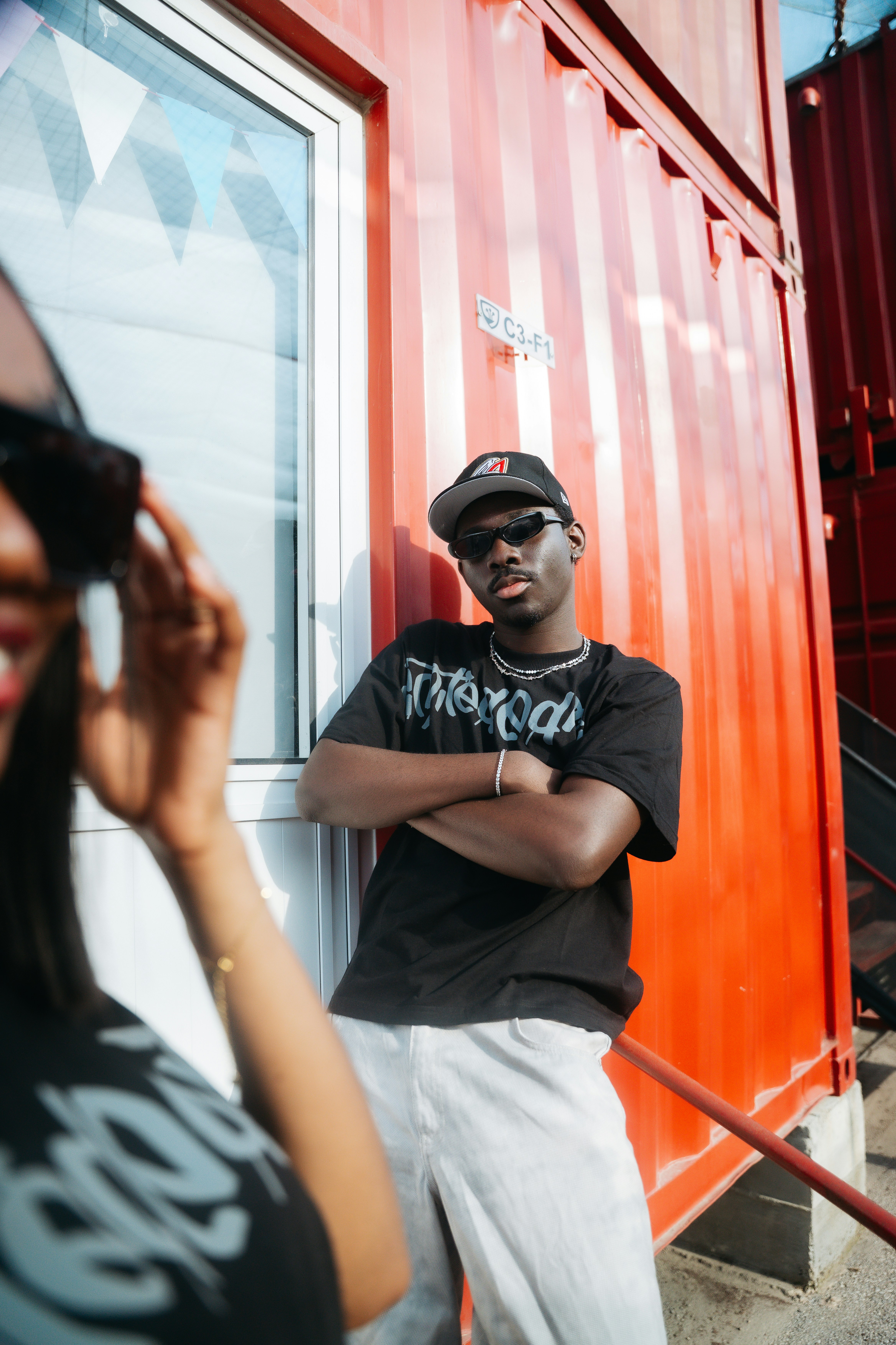 Crossed Arms, Red Wall: A Confident Moment in Neon Light
