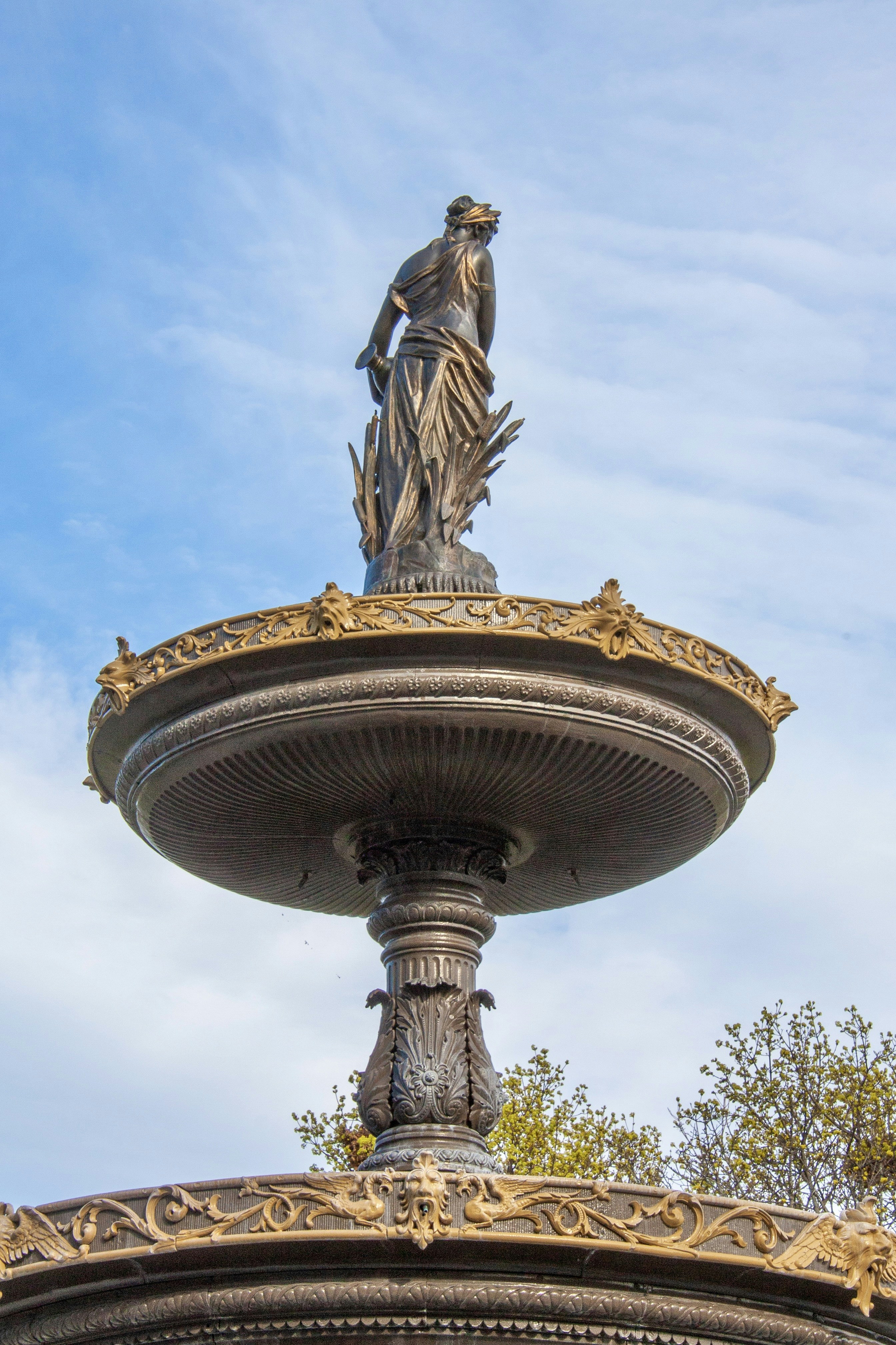 The Sentinel of Bronze: A Statue Crowned by Ornate Basin