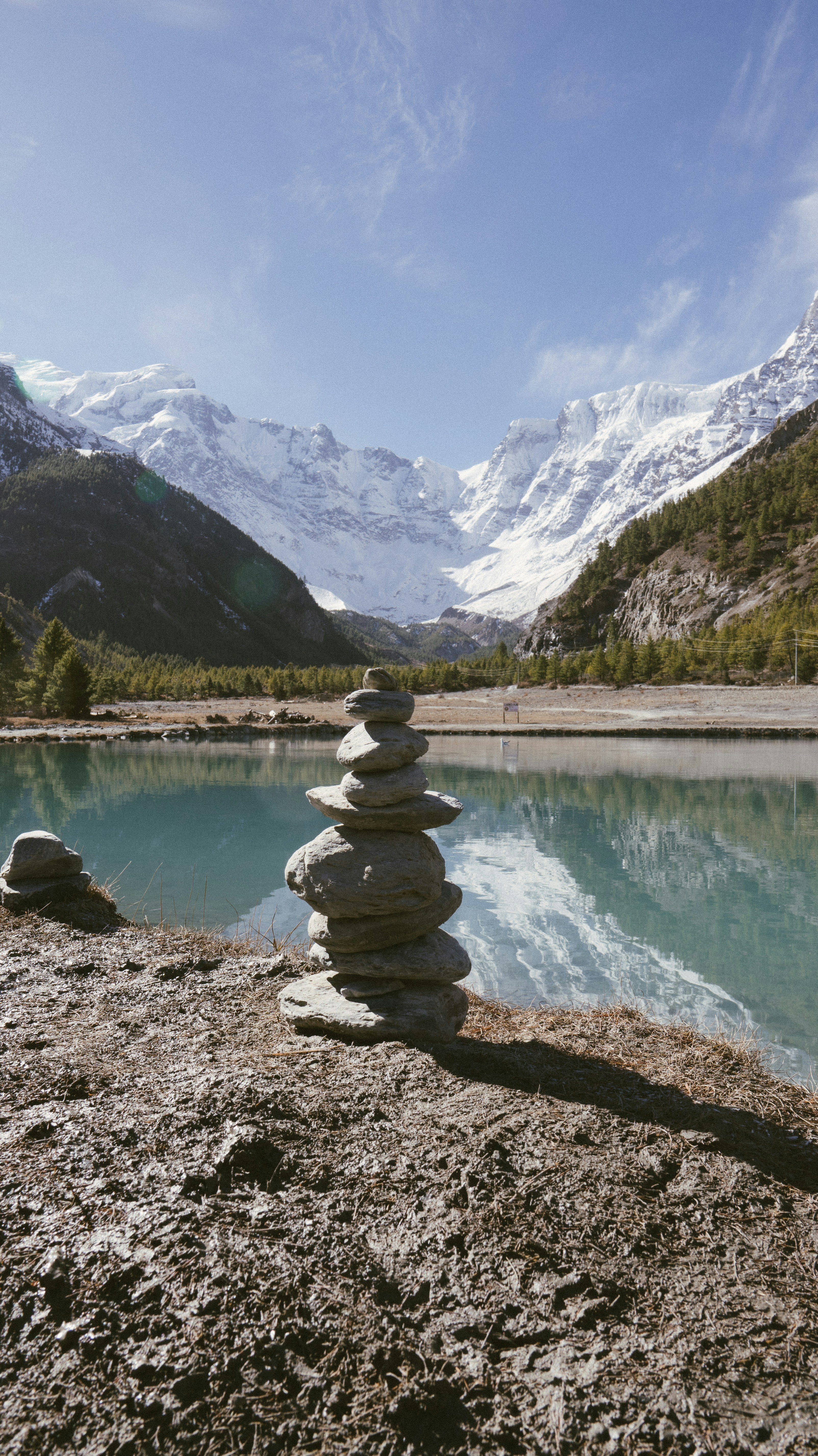 Stacked Stones by a Glacier Lake under Alpine Peaks