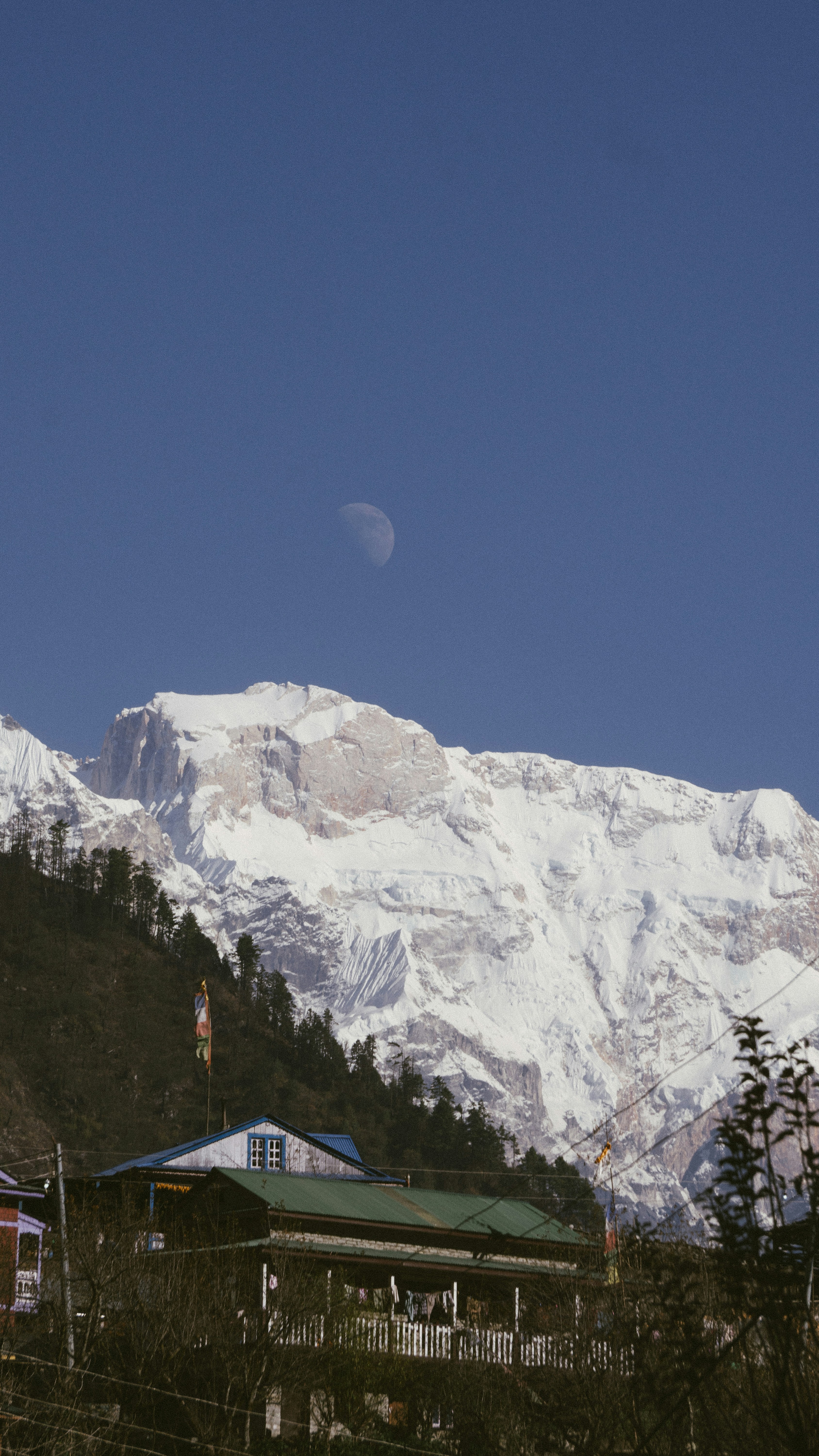 Moon above the snowbound peak and village beneath