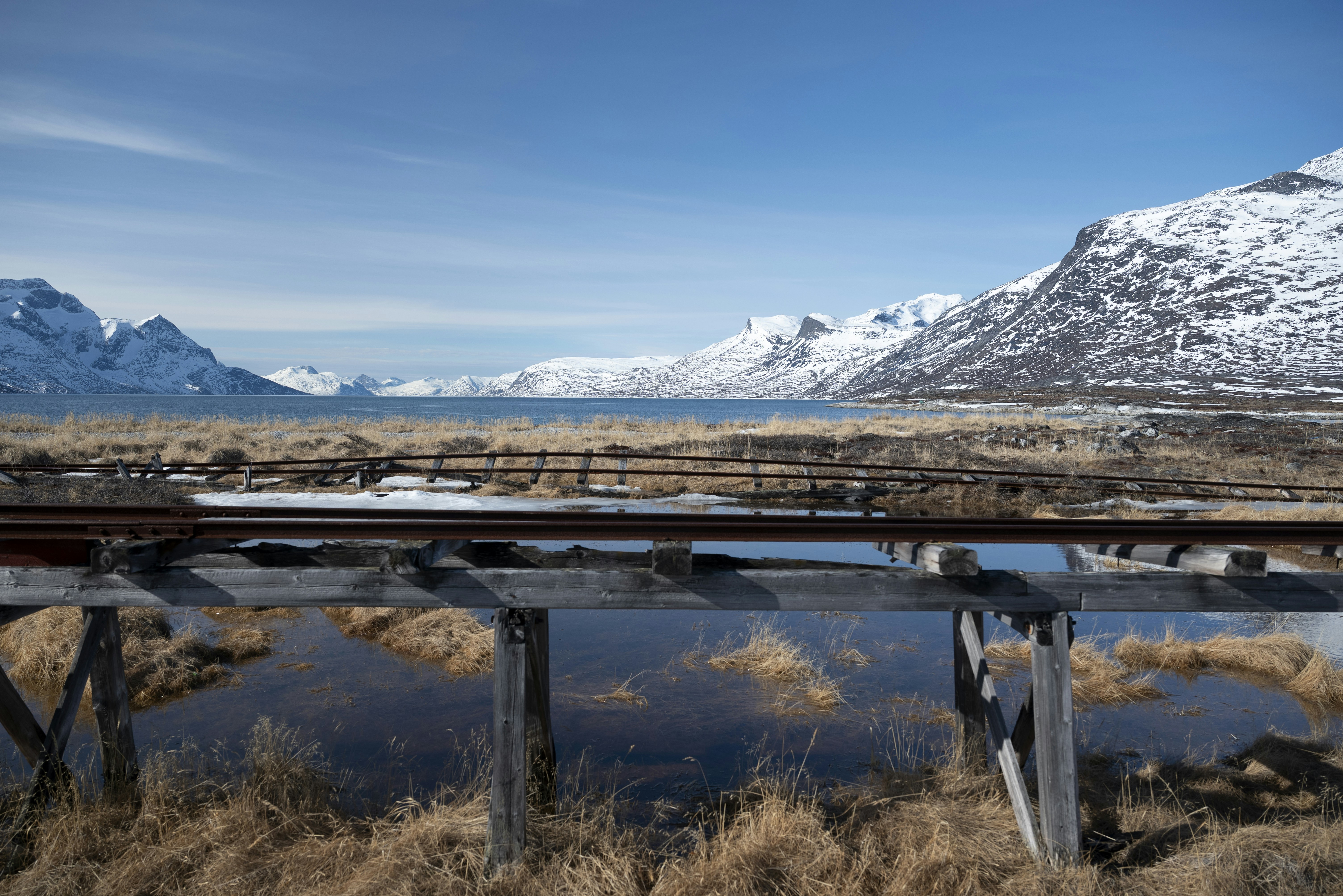 Rails Across the Tundra: Snowcapped Peaks Beyond a Weathered Track