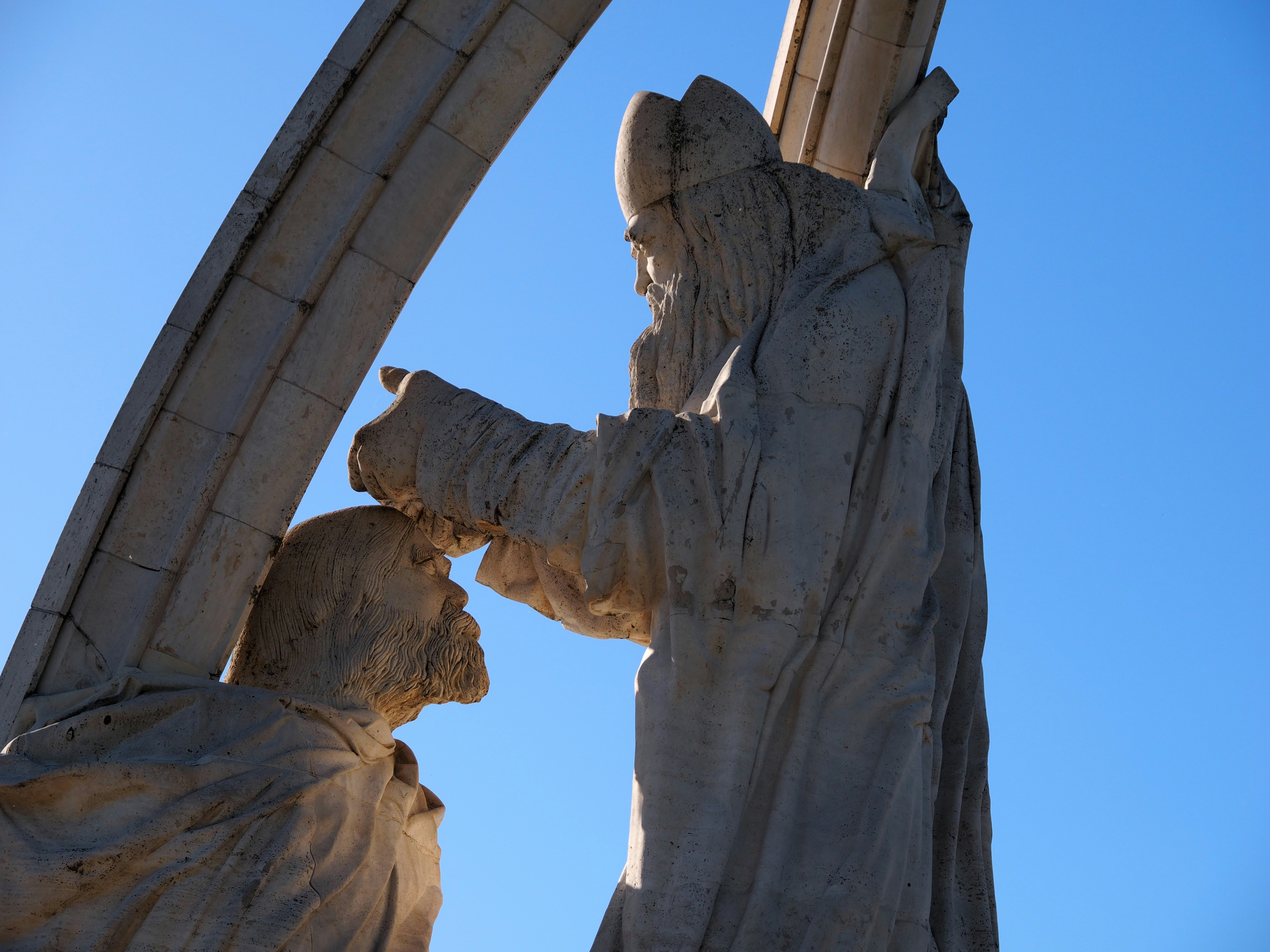 Hands Raised in Stone: A Monumental Exchange Under Blue Skies