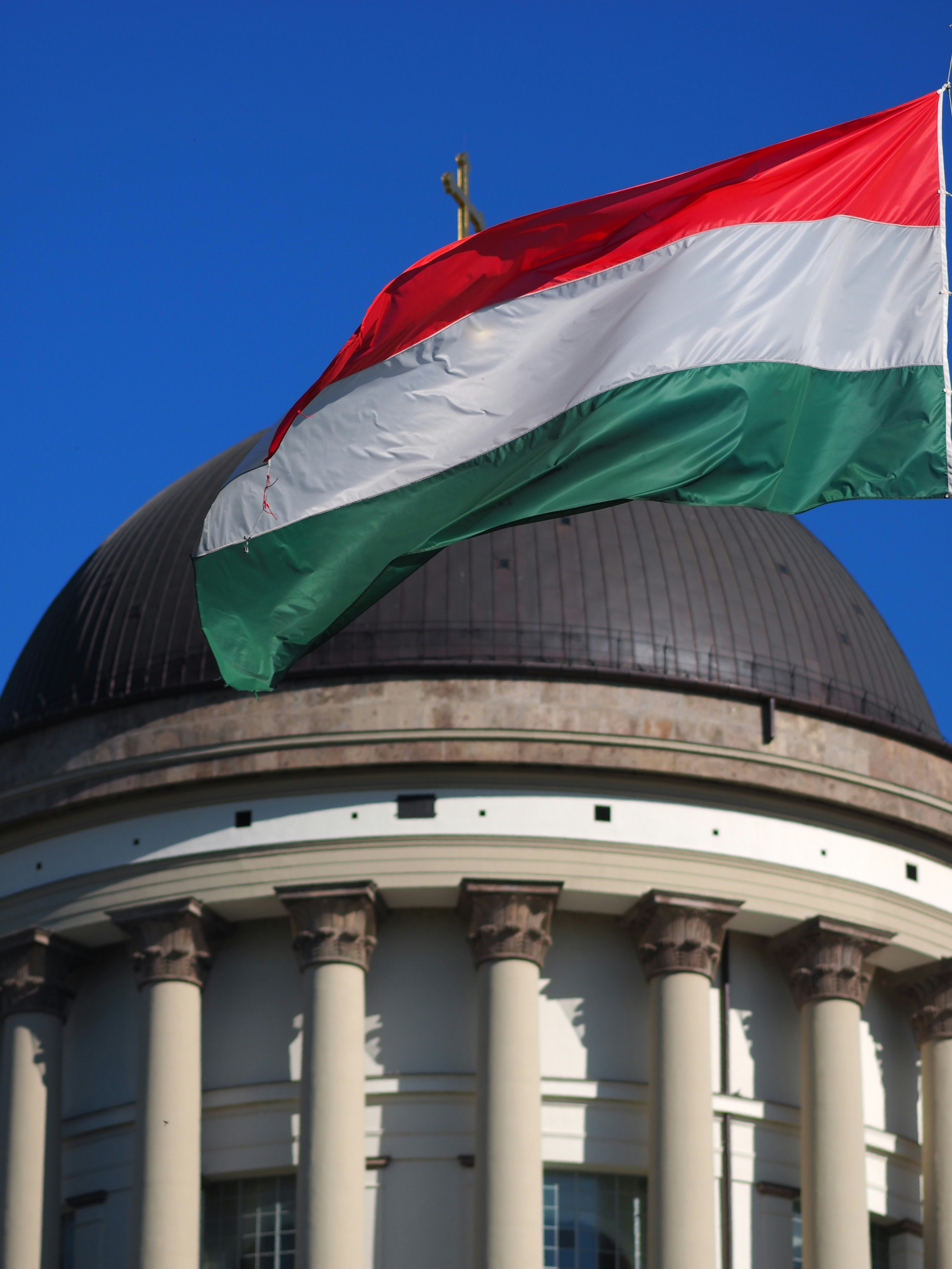Flag Over Dome: A Hungarian Symbol Fluttering Above Neoclassical Pillars