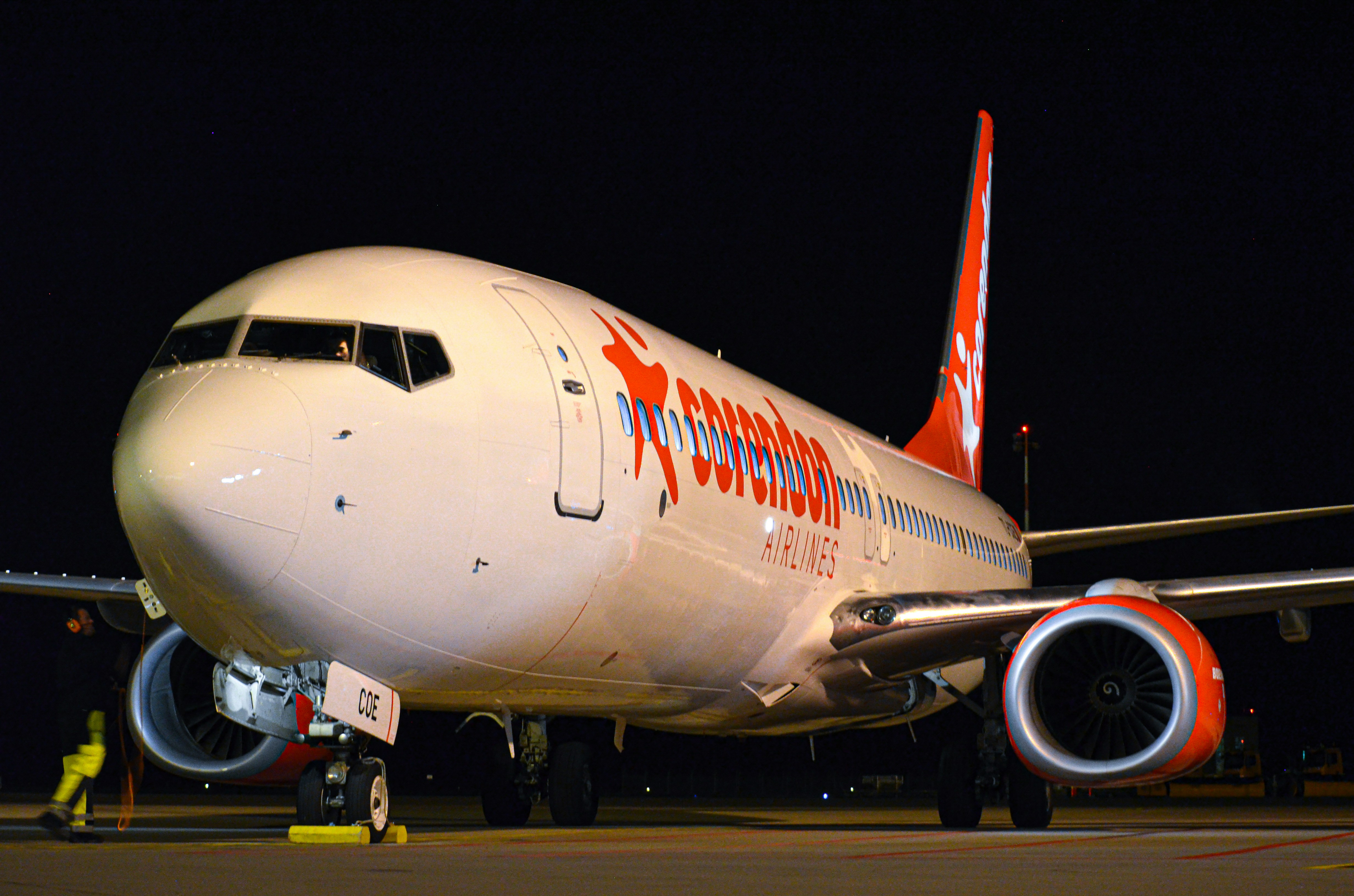 Narrow-view Night Arrival: A Red-Accented Jet Steaming Under Runway Lights