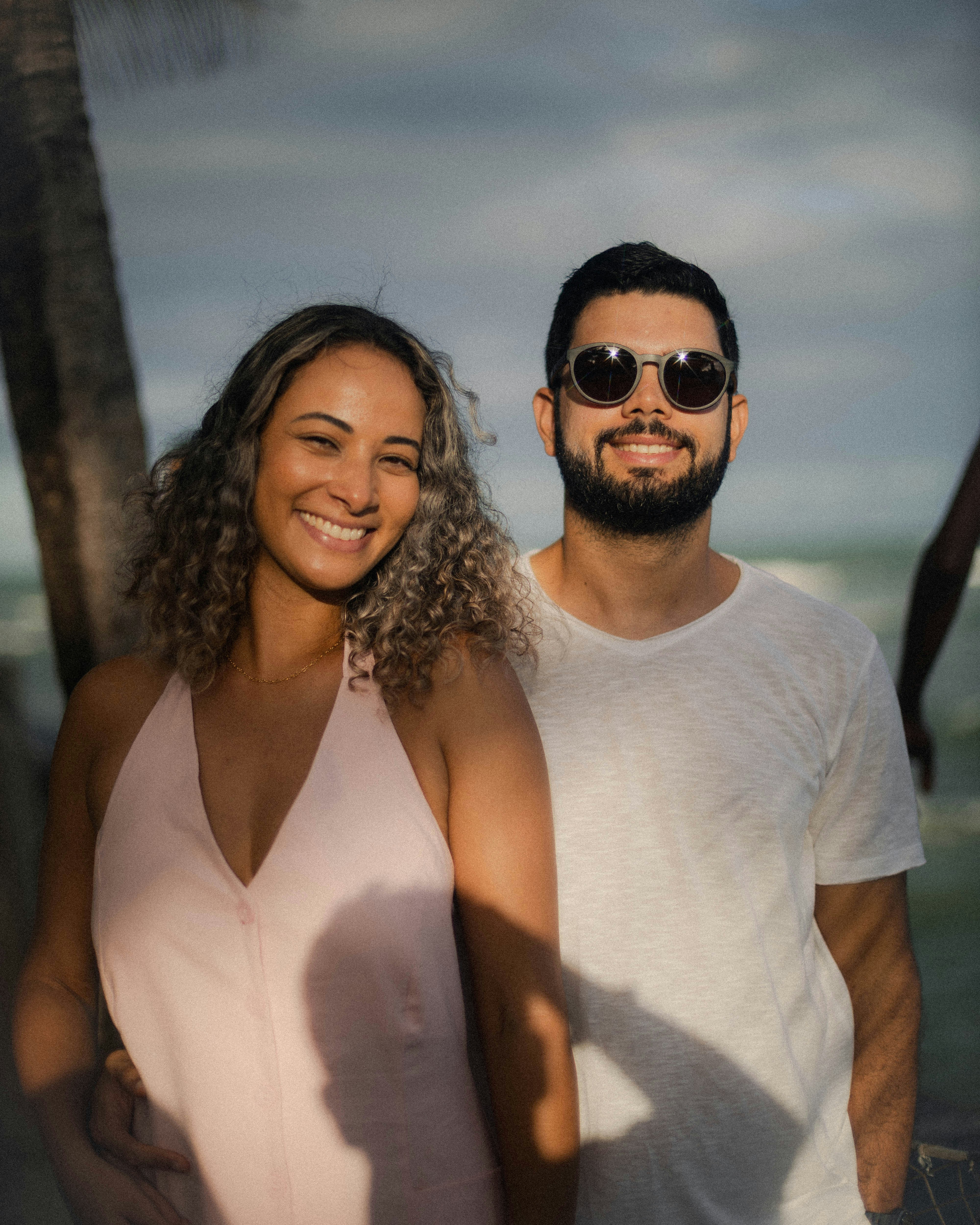 Sunlit Shoreside Smile: A Happy Pair Beneath Palm Shadows
