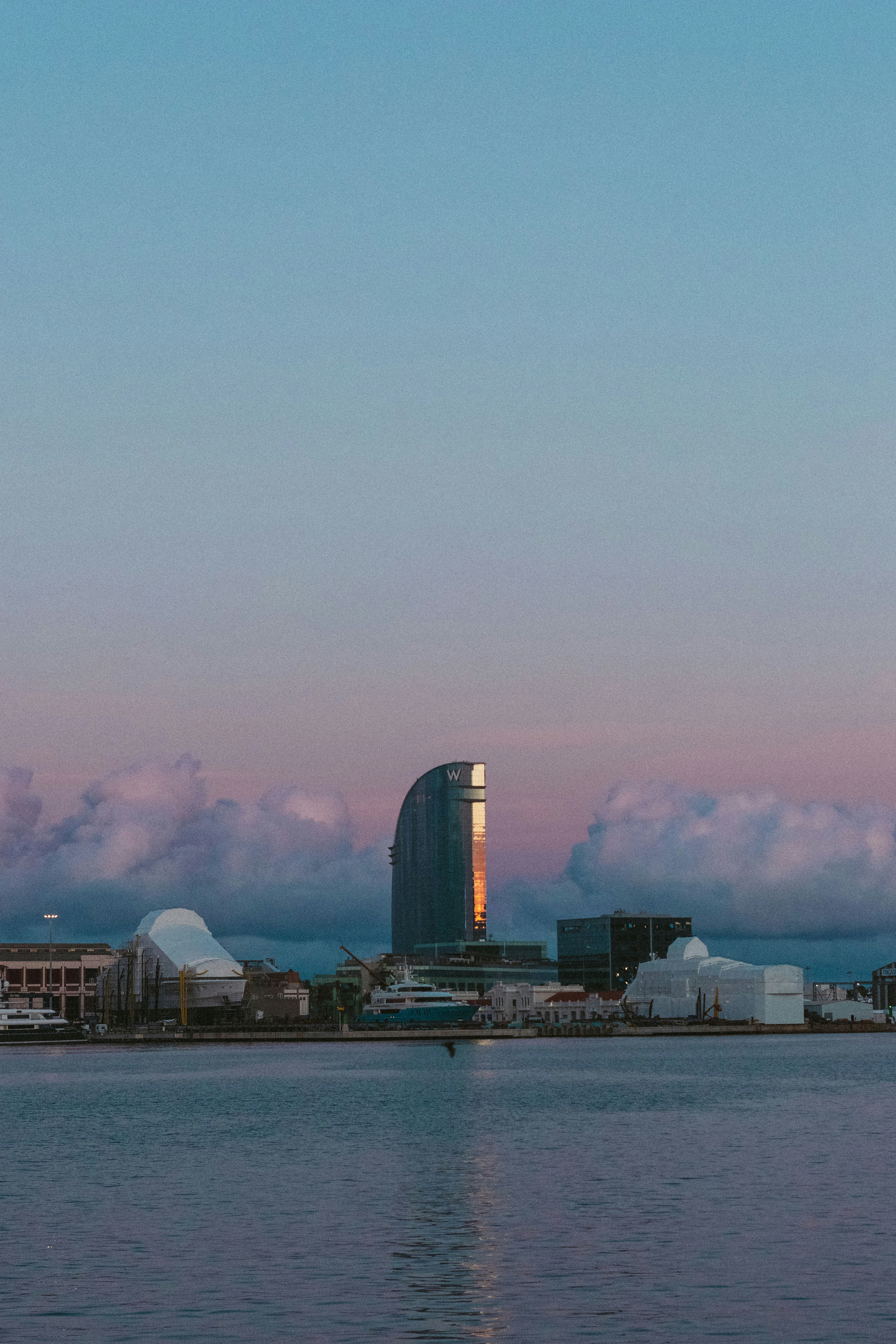Harbor silhouette at dusk: a modern city crest rises above tranquil water