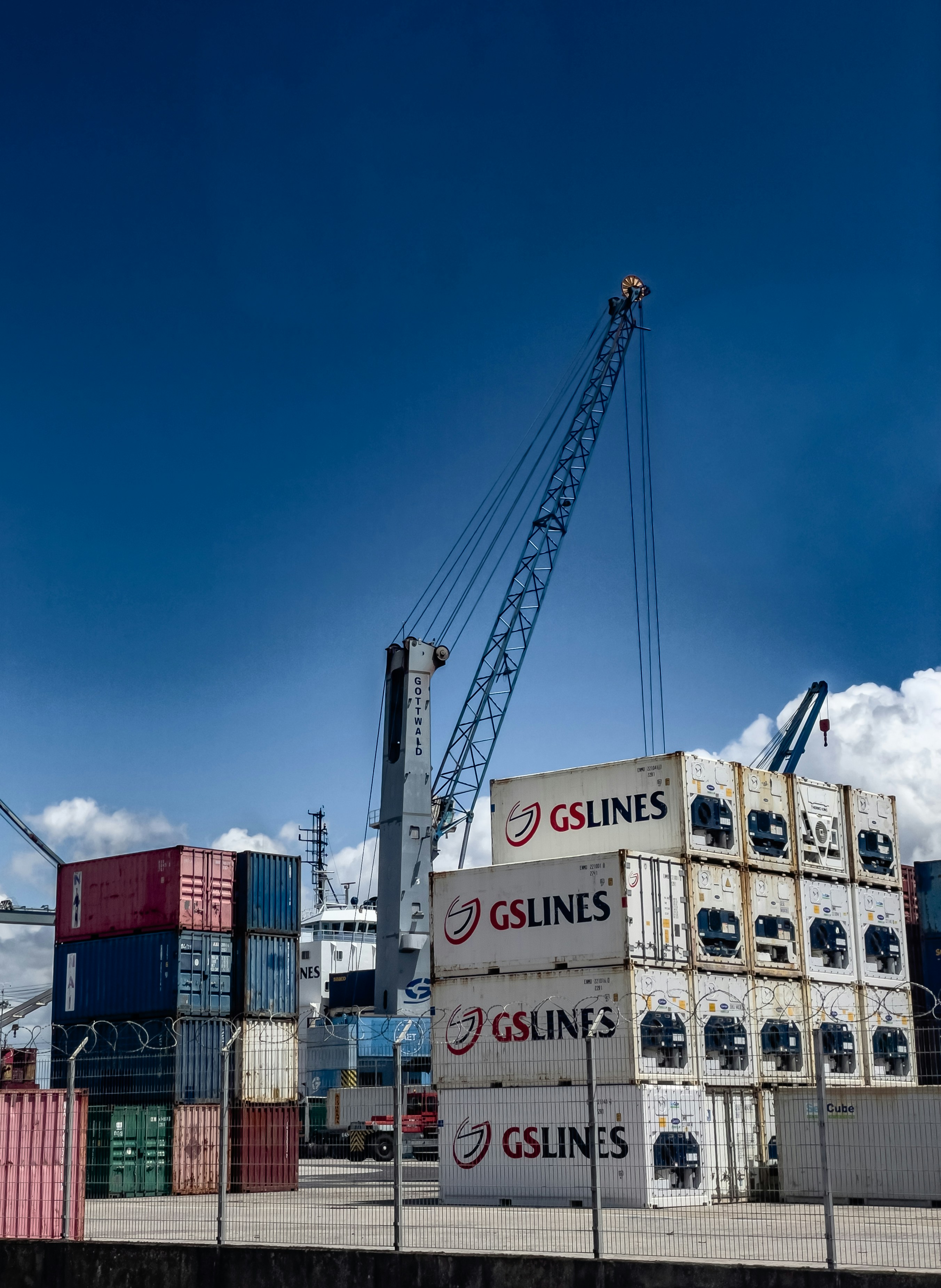 Crane and stacked containers loom over a busy shipping yard