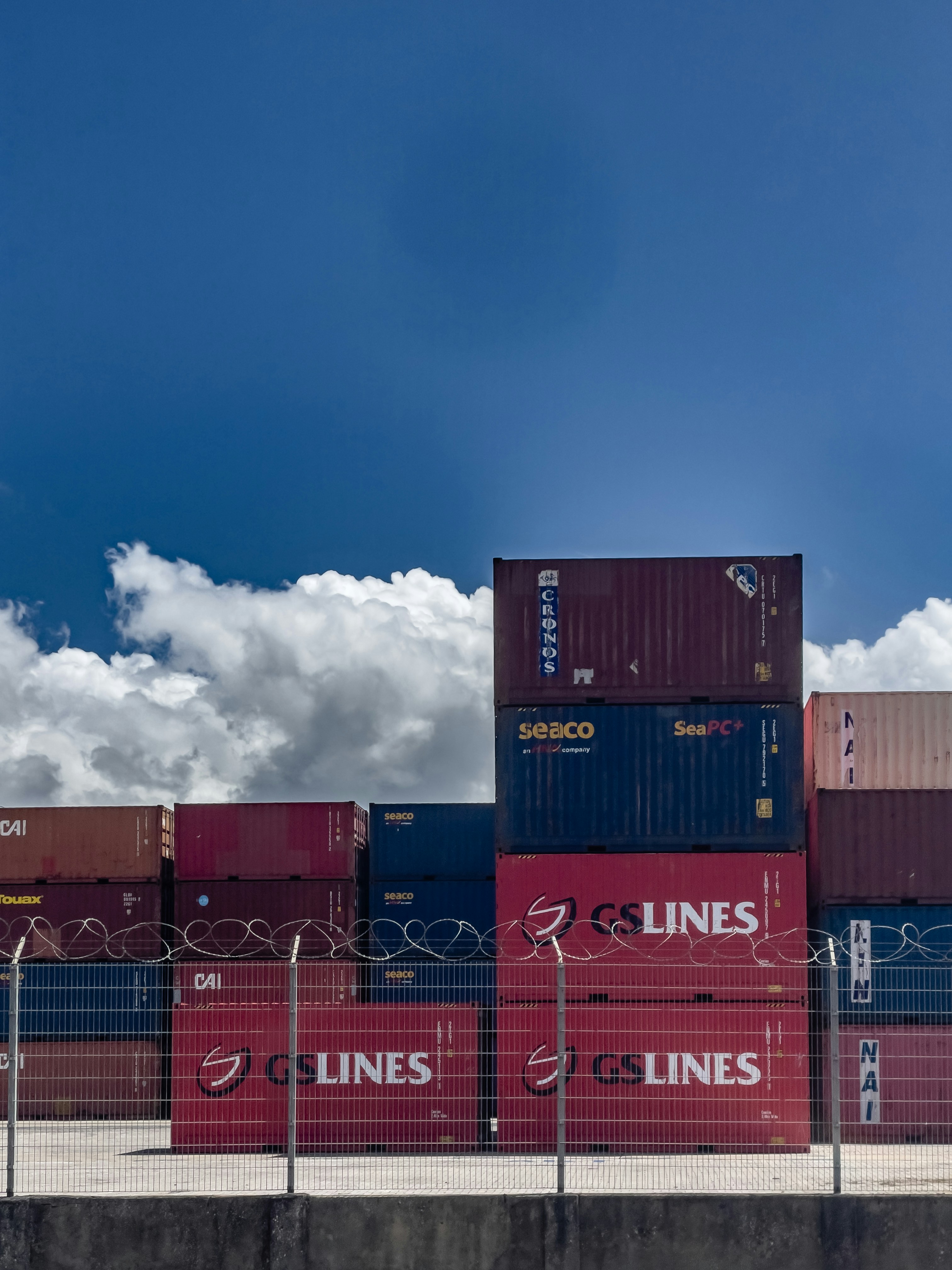 Stacks of Cargo: A Quiet Horizon Behind the Barbed Fence