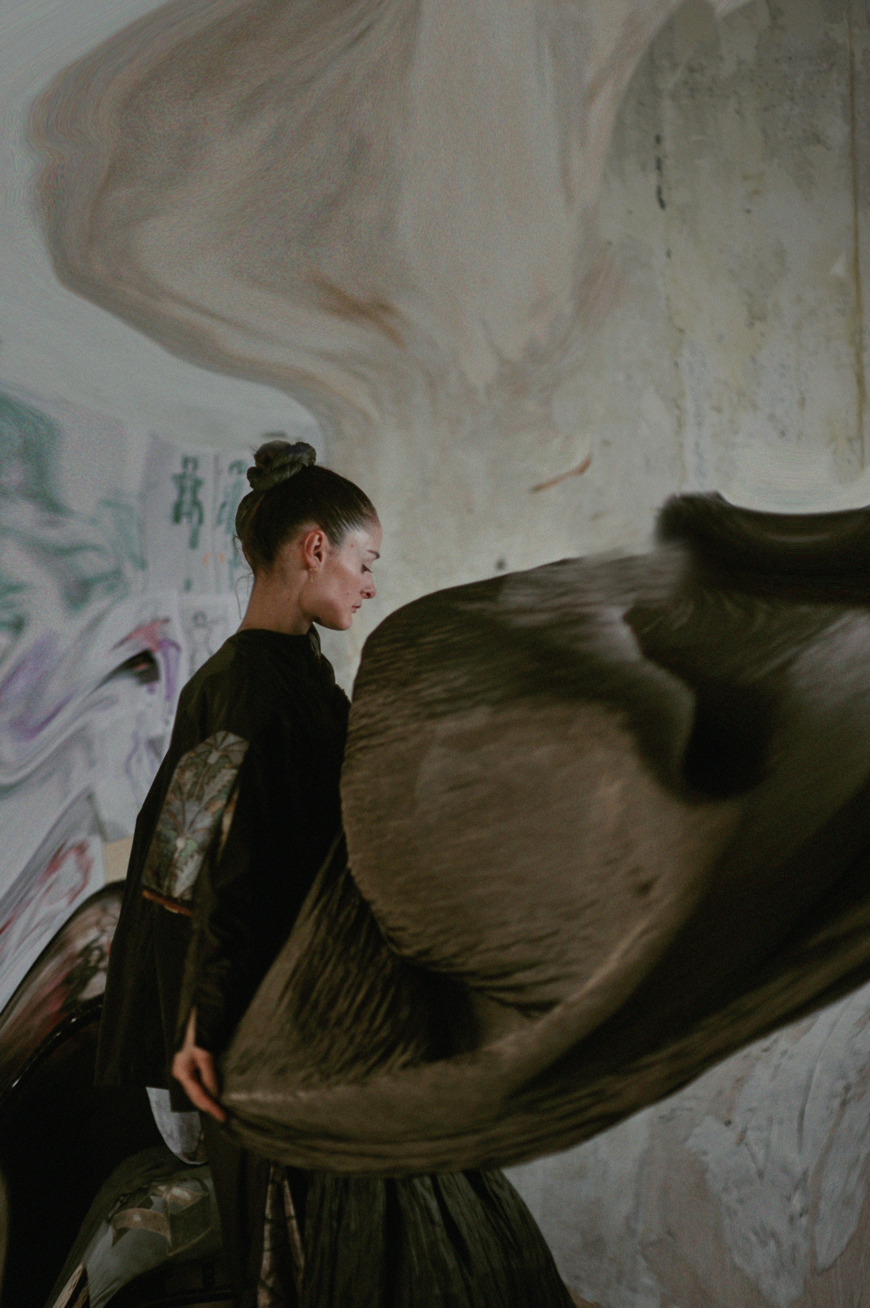 Portrait in Motion: A Quiet Gaze Amidst swirling fabric and graffiti