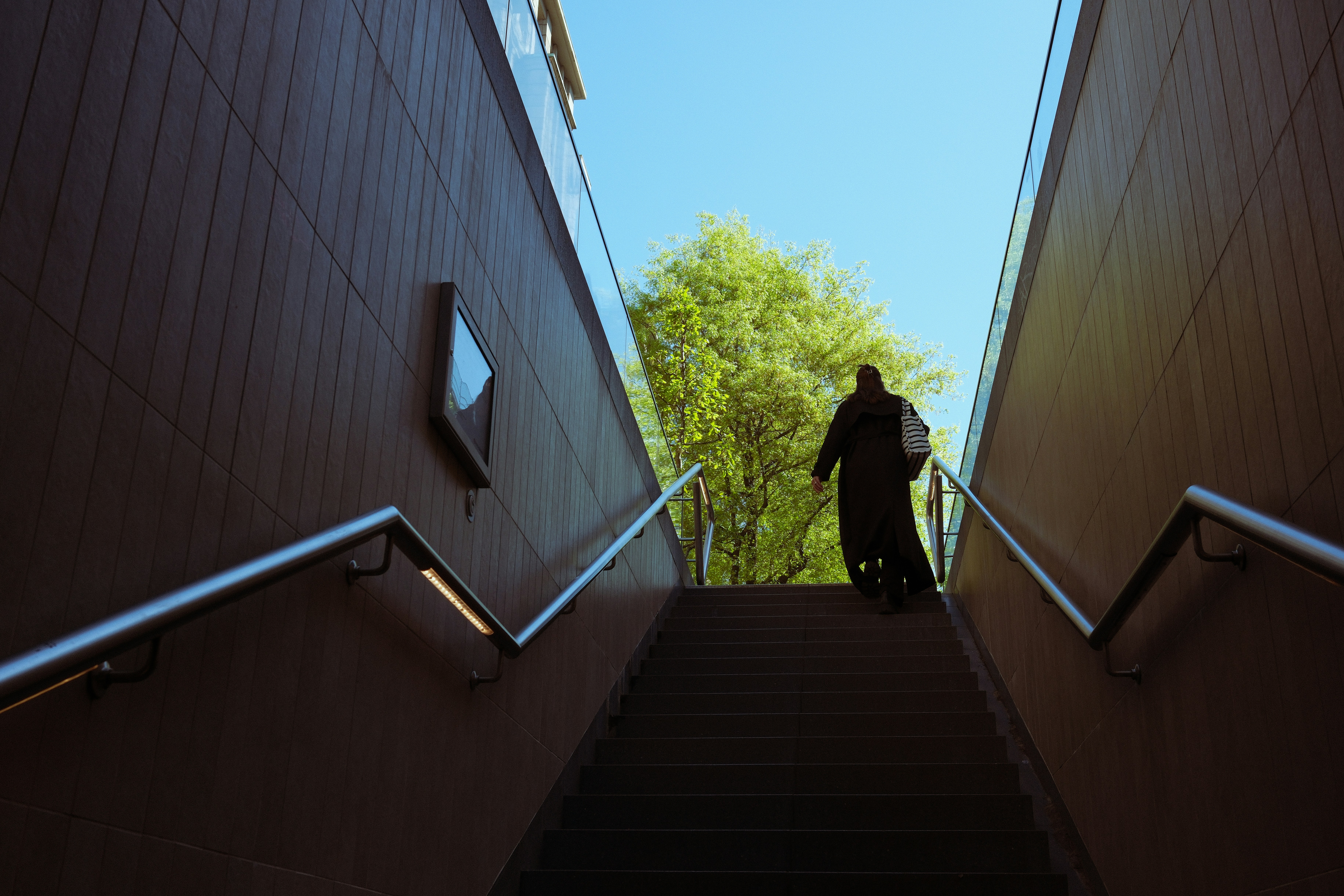 Elevated Ascent: The solitary traveler at a sunlit stairwell