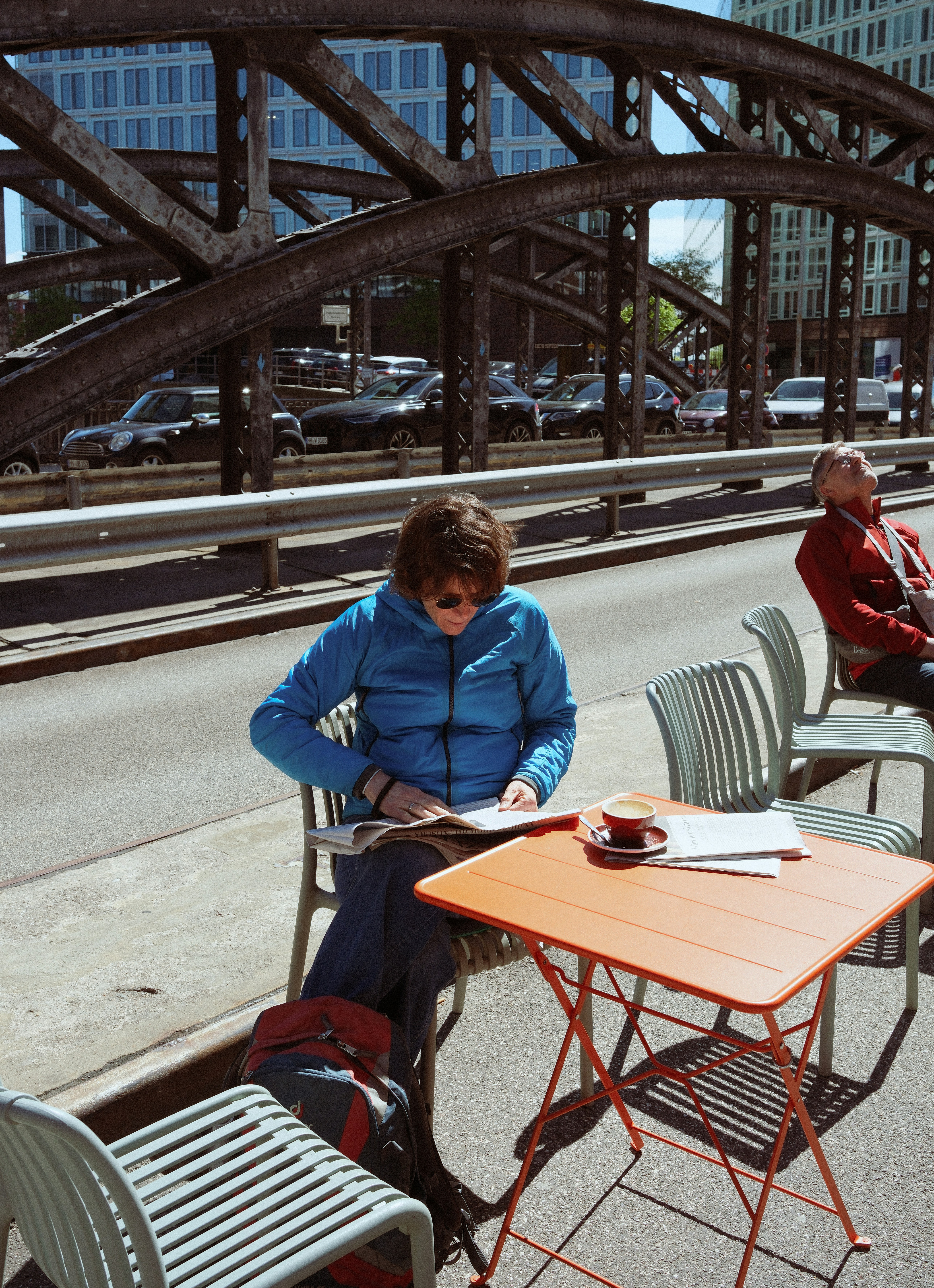 Blue Jacket, Focused Reader: A Quiet Moment at the Outdoor Café