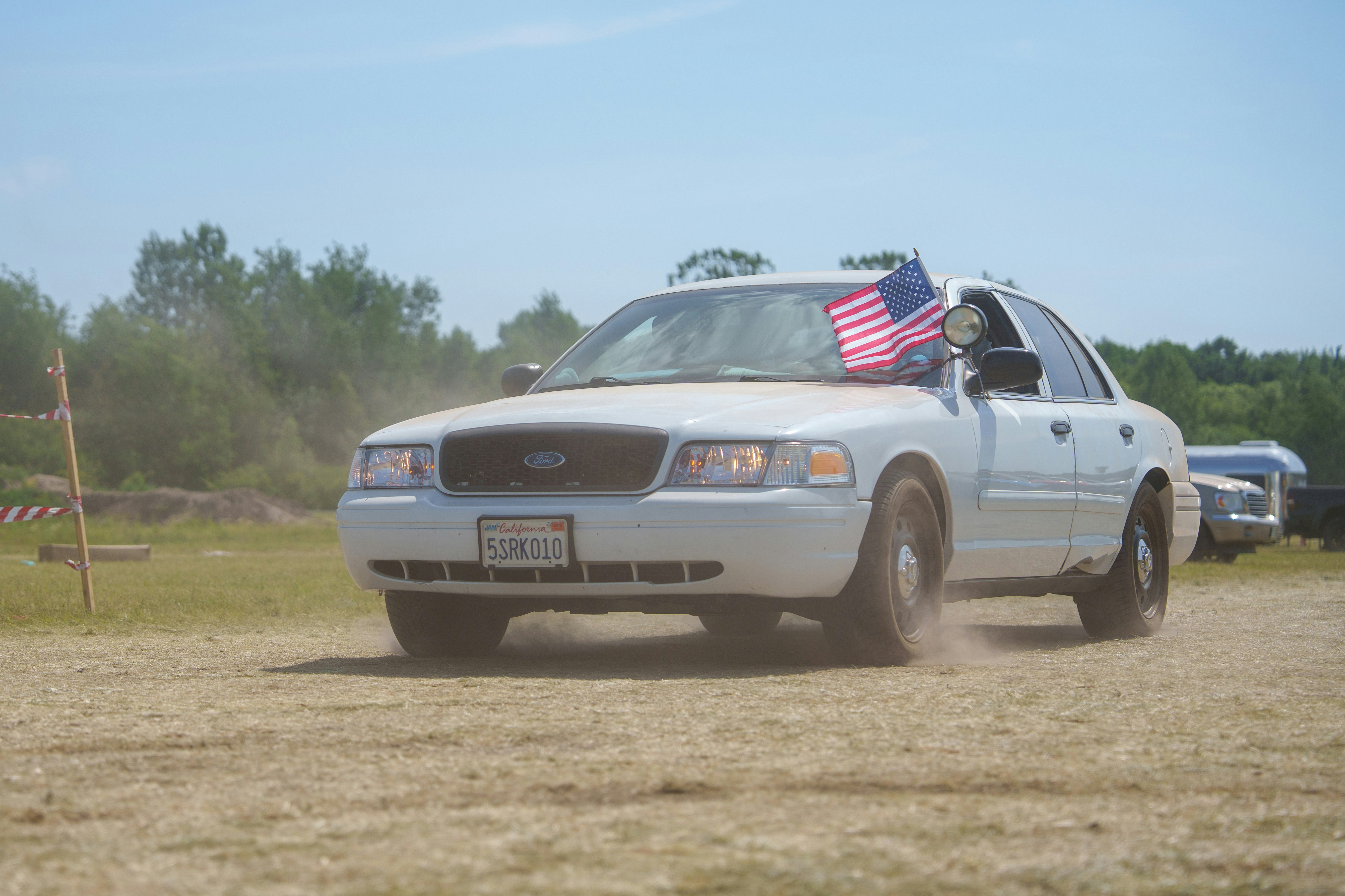 Patriotic Ride: A Dusty Parade in a White Ford