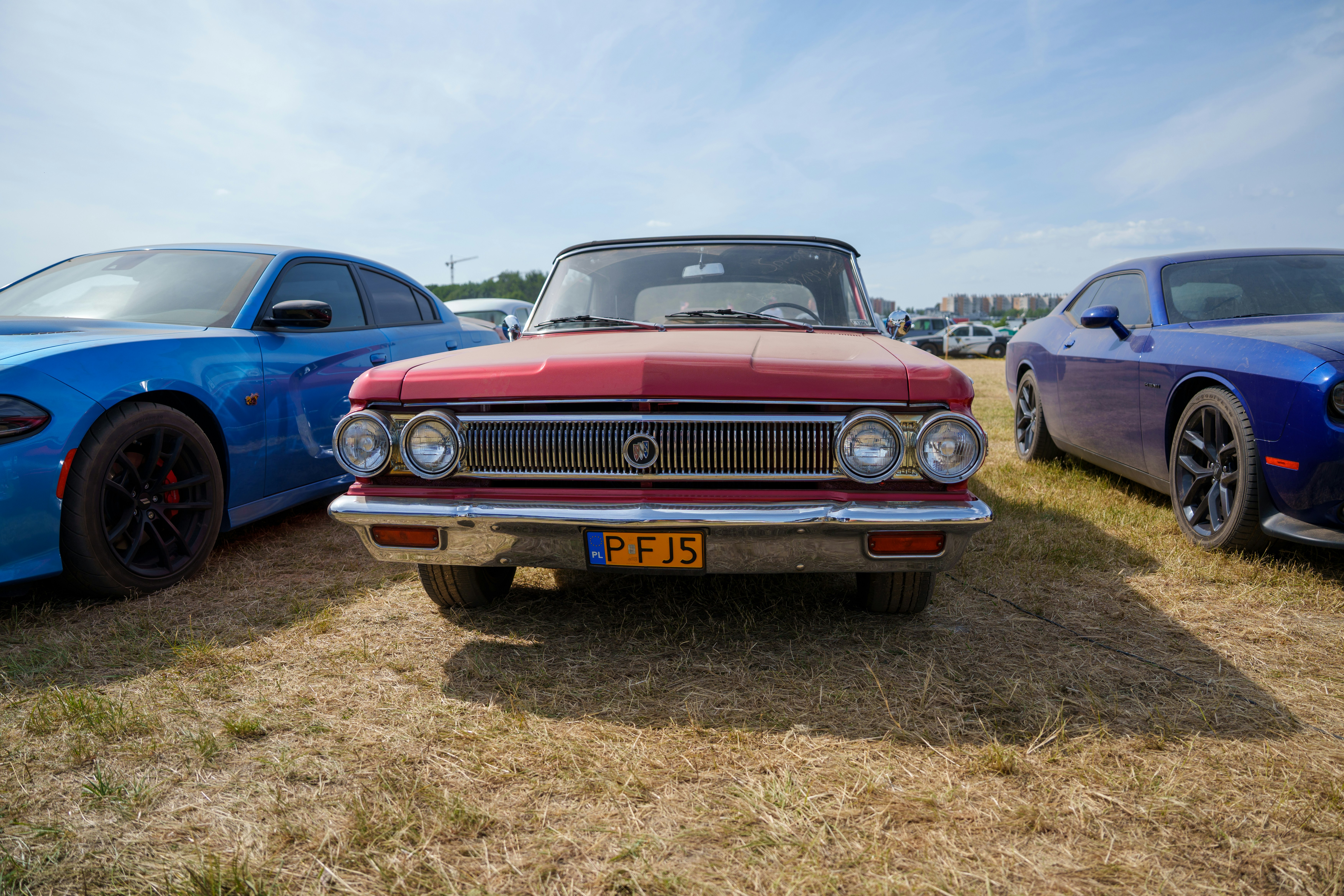 Center Stage Classic: A Red Vintage Convertible Between Modern Blues