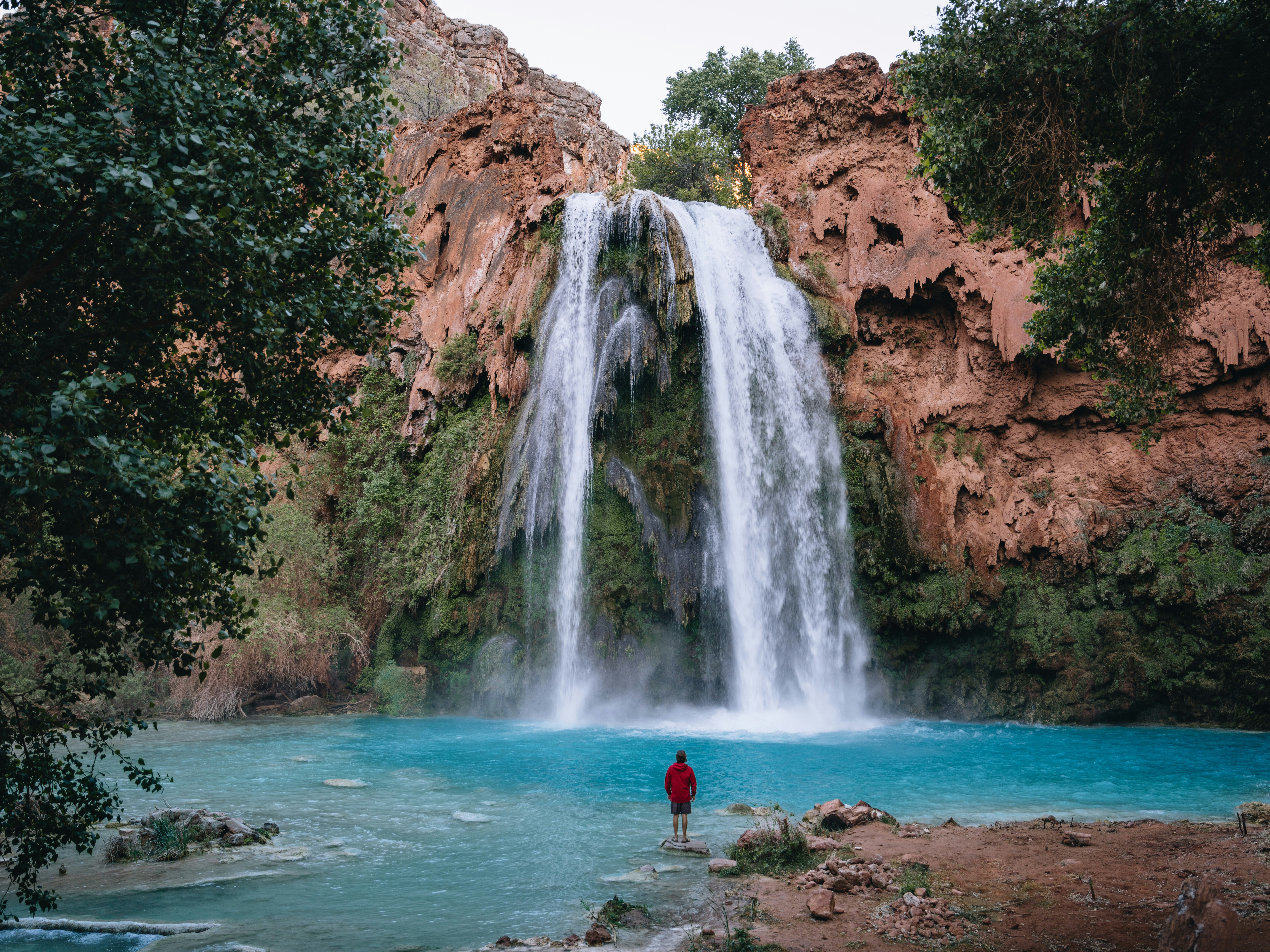 Turquoise Sands and Waterfall: A Lone Visitor at the Vivid Cascade