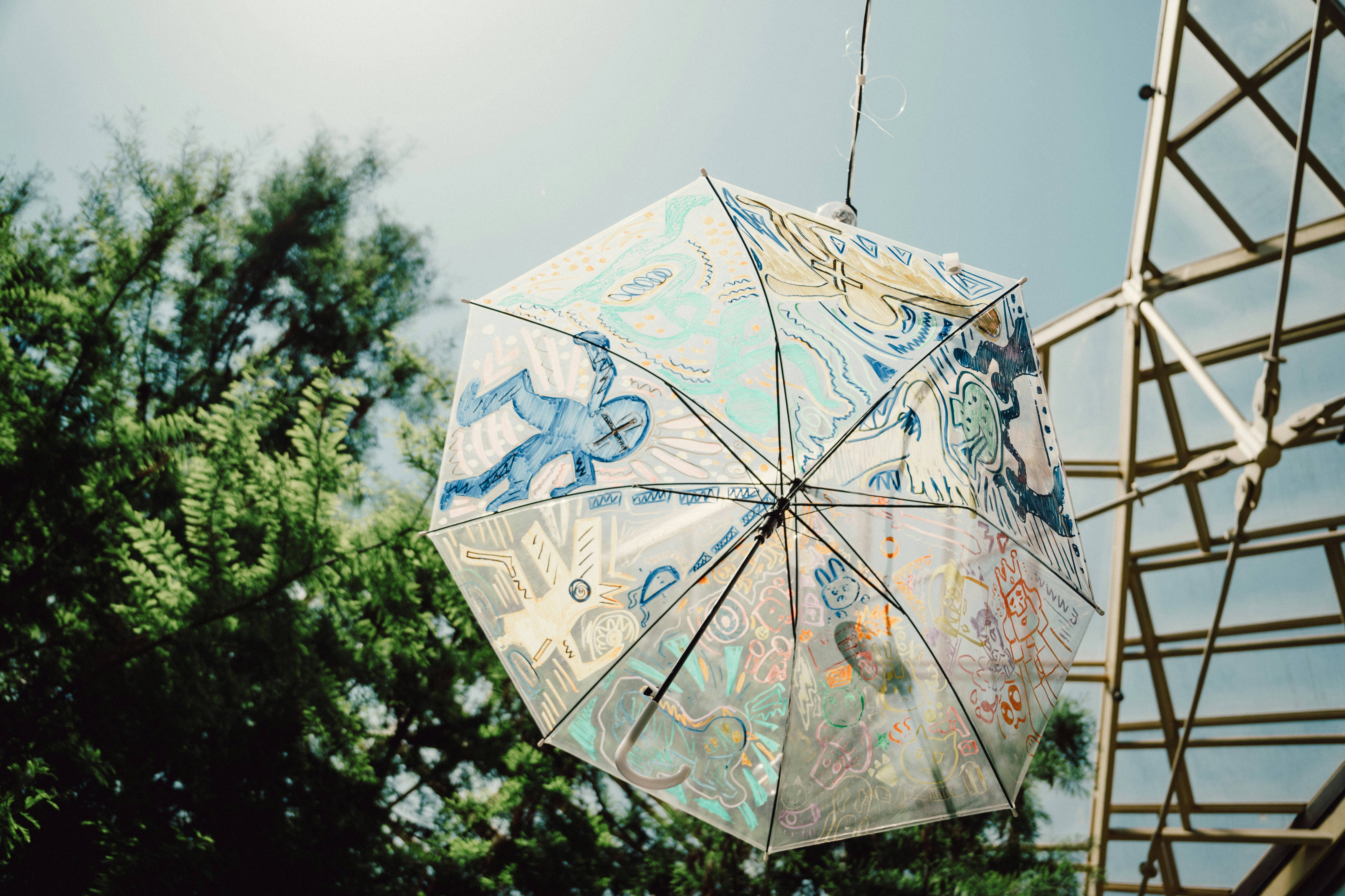 Floating Artistry: Graffitied Umbrella against Skyward Framework