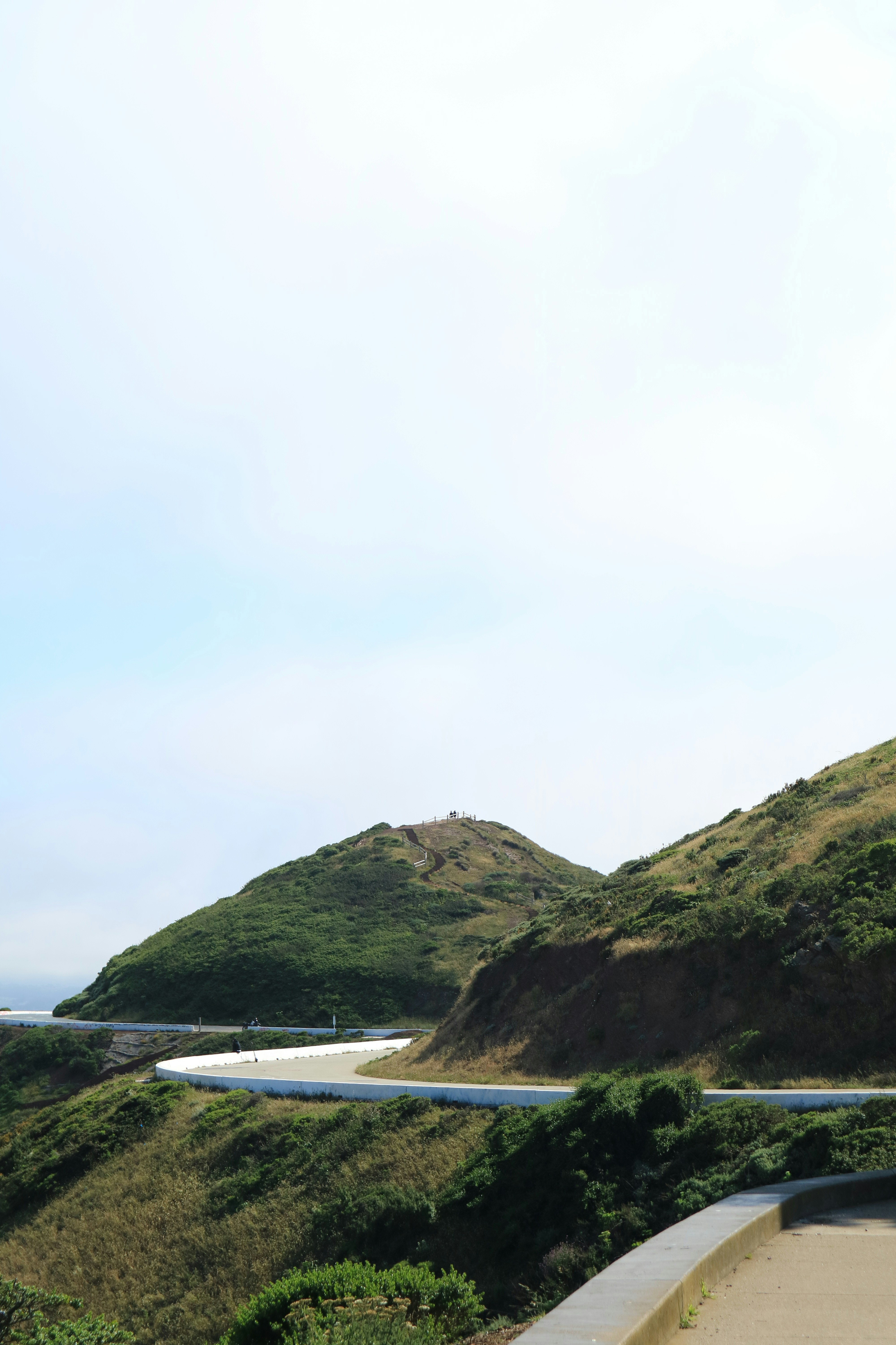 Winding Coastal Road Circles a Greener Ridge under Open Sky