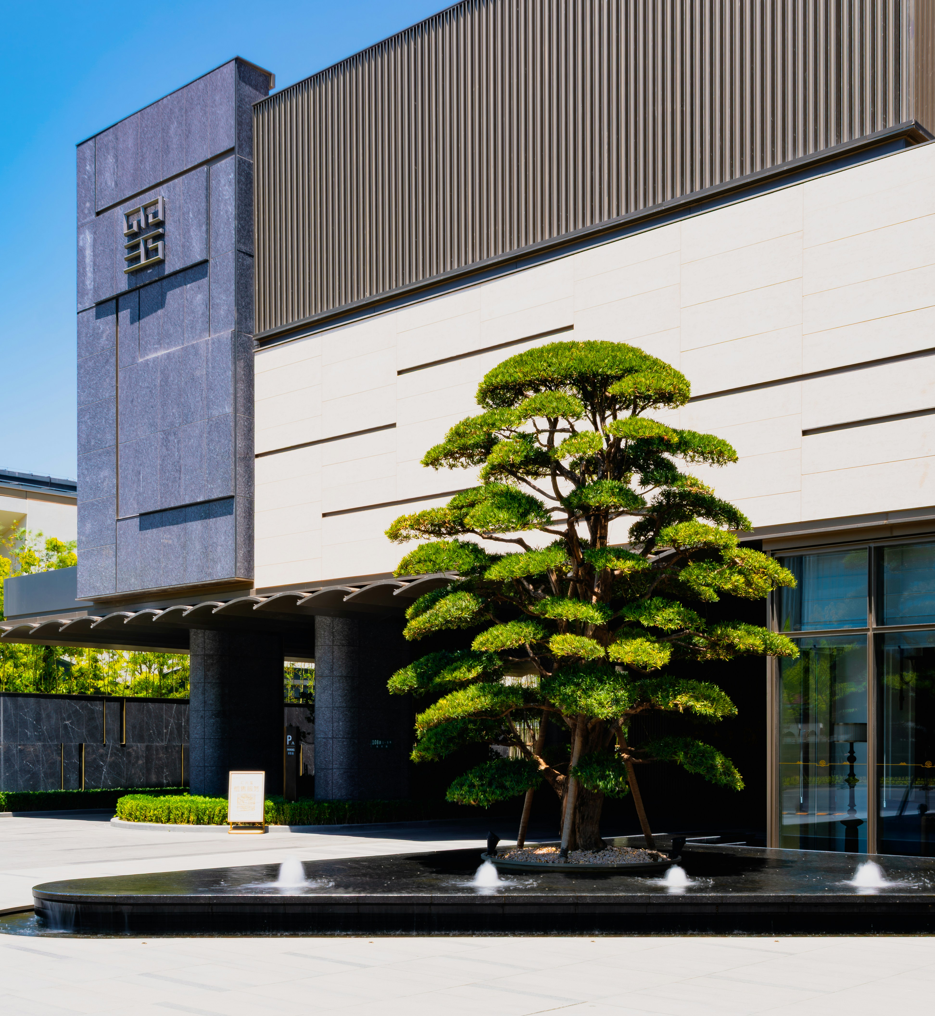 Subtly Sculpted Greenery Surrounded by Modern Facade