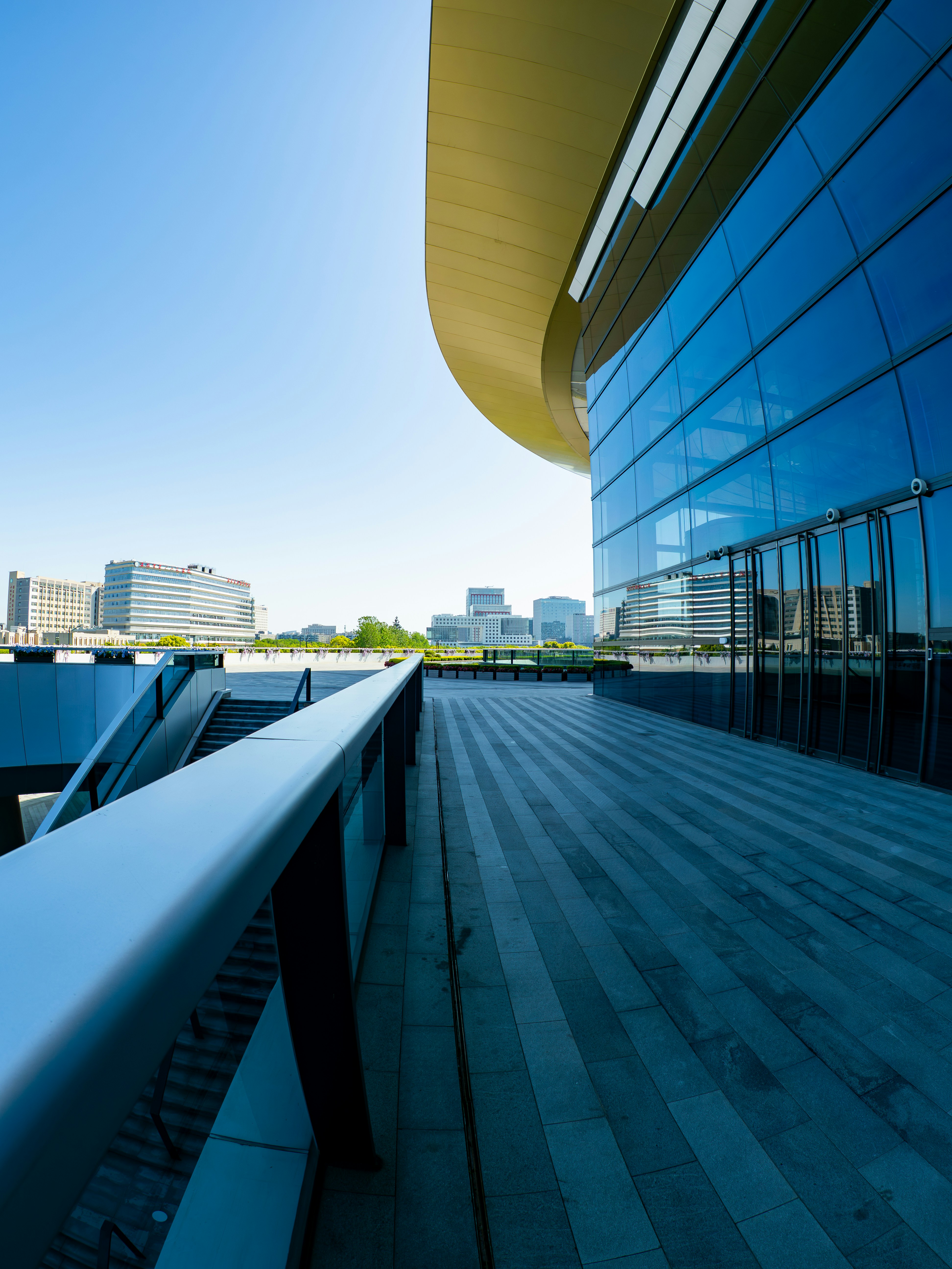 Curved Yellow Canopy Over a Glass Facade Reflects a Modern City Walk