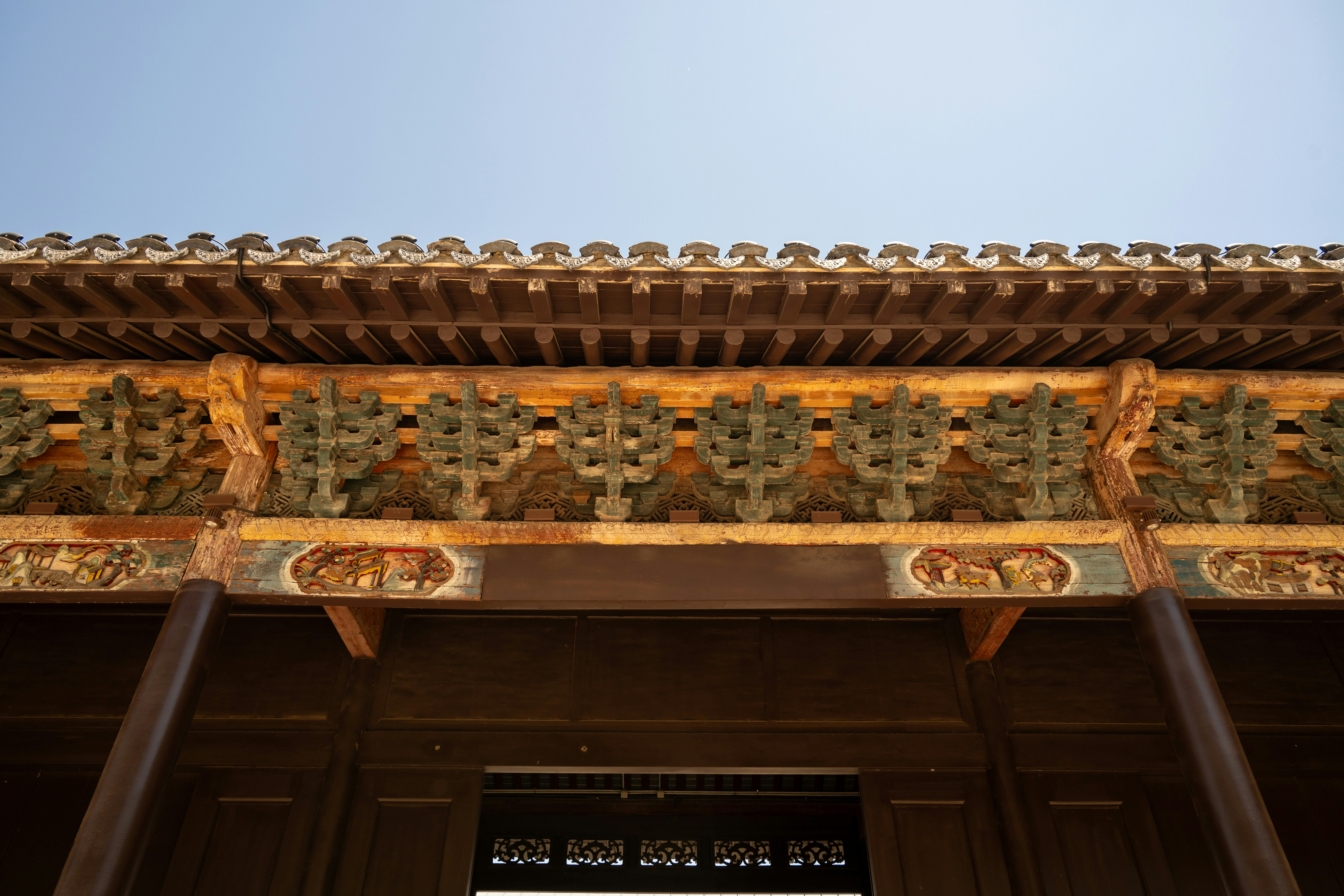 Sunlit Temple Eaves: Wooden Carvings and Ceremonial Roofline