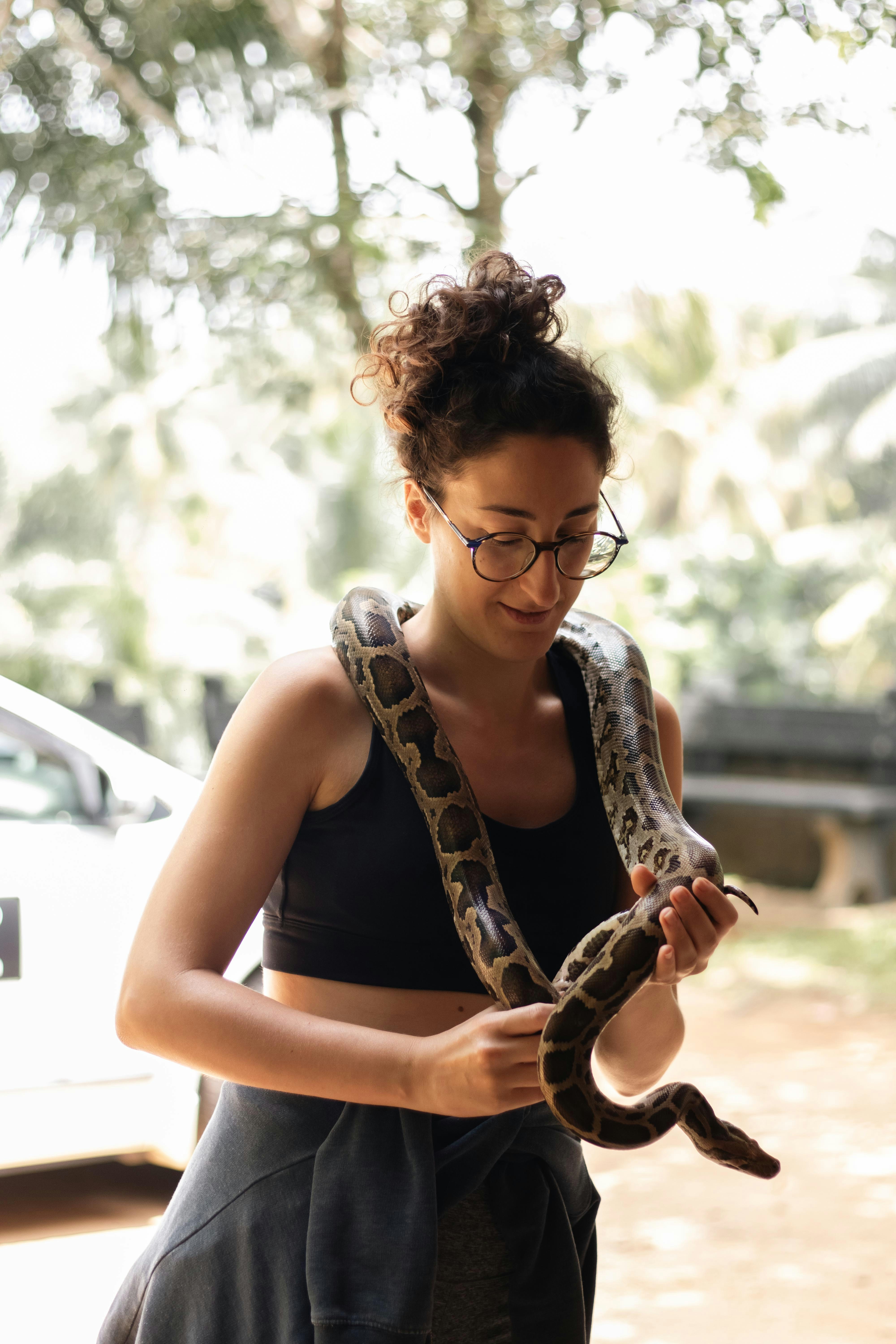 Snake Charmer in the Park: A Woman Holds a Gentle Coil of Snake