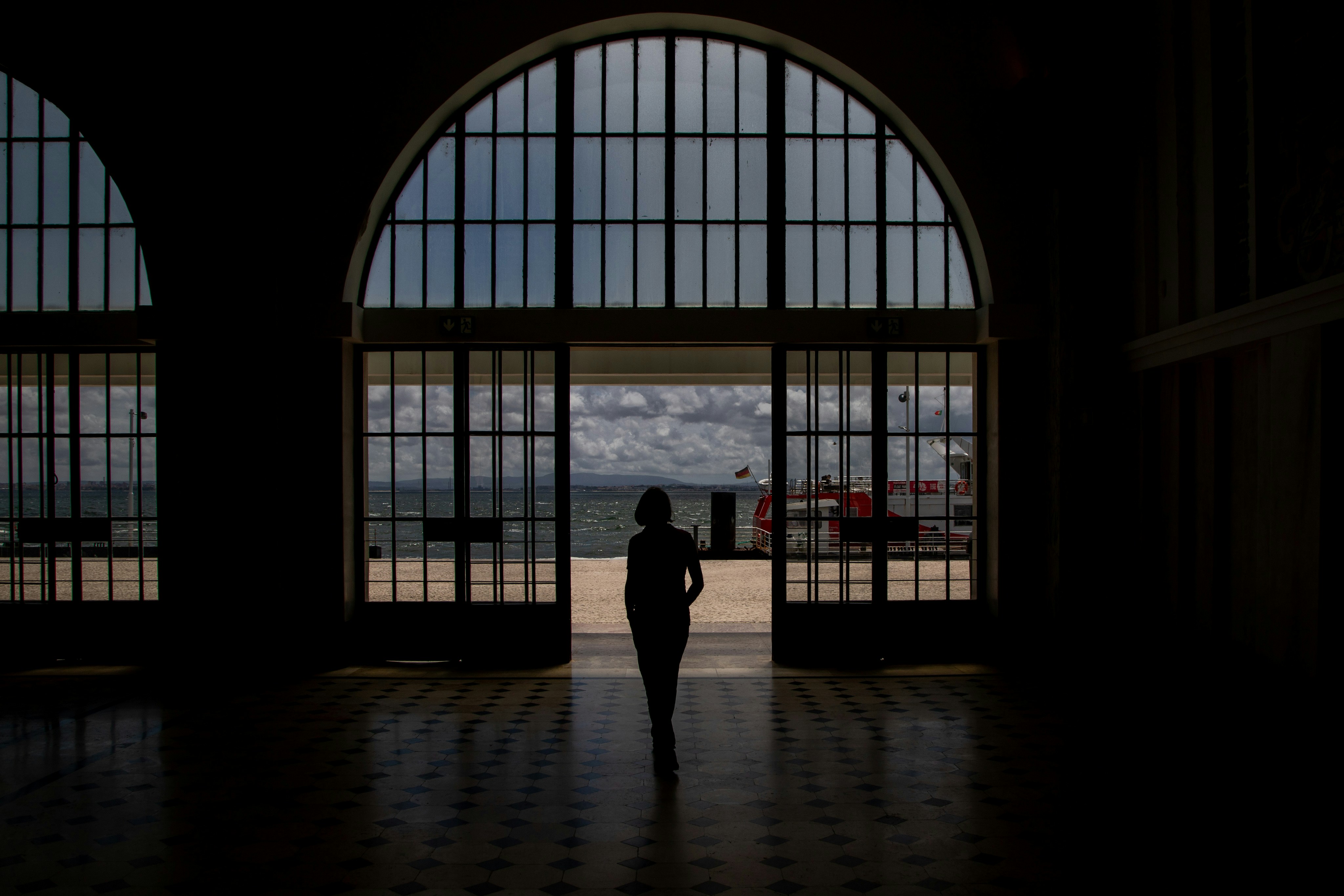 Silhouette in the Arch: A figure stepping into daylight from a grand doorway