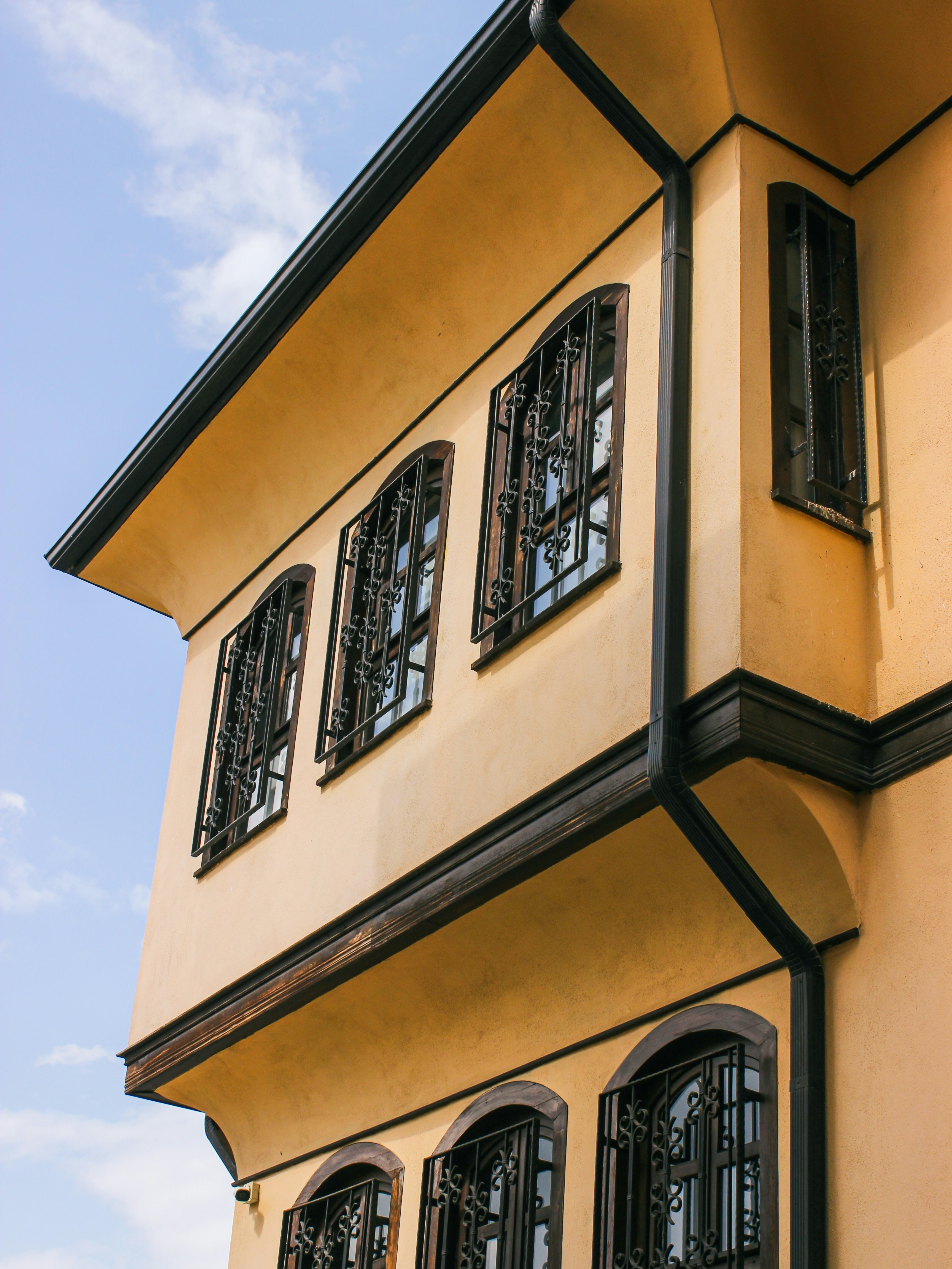 Sunlit Facade: Arched Windows and Wrought-Iron Detailing