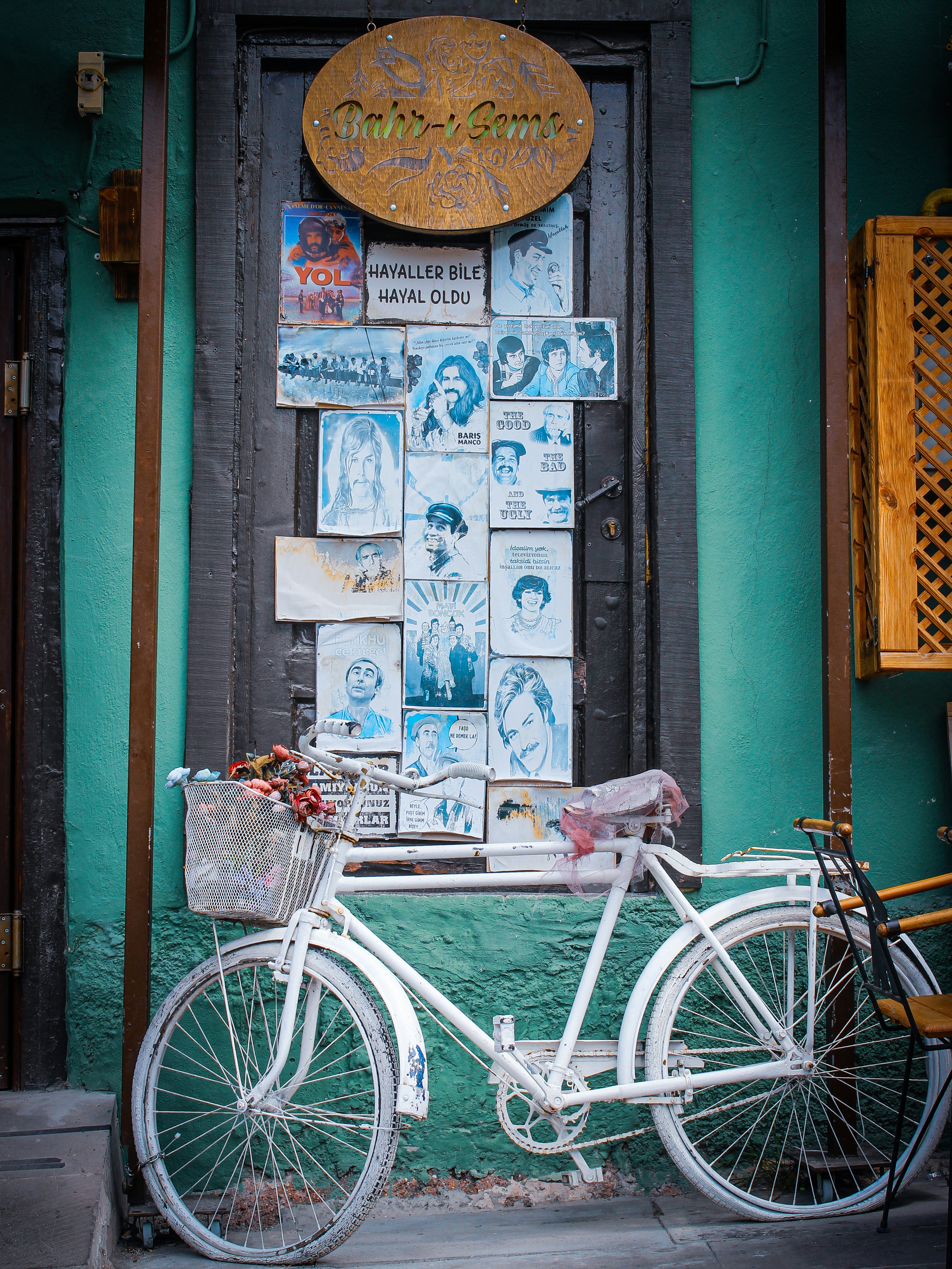 White bicycle in front of a mural-clad teal doorway