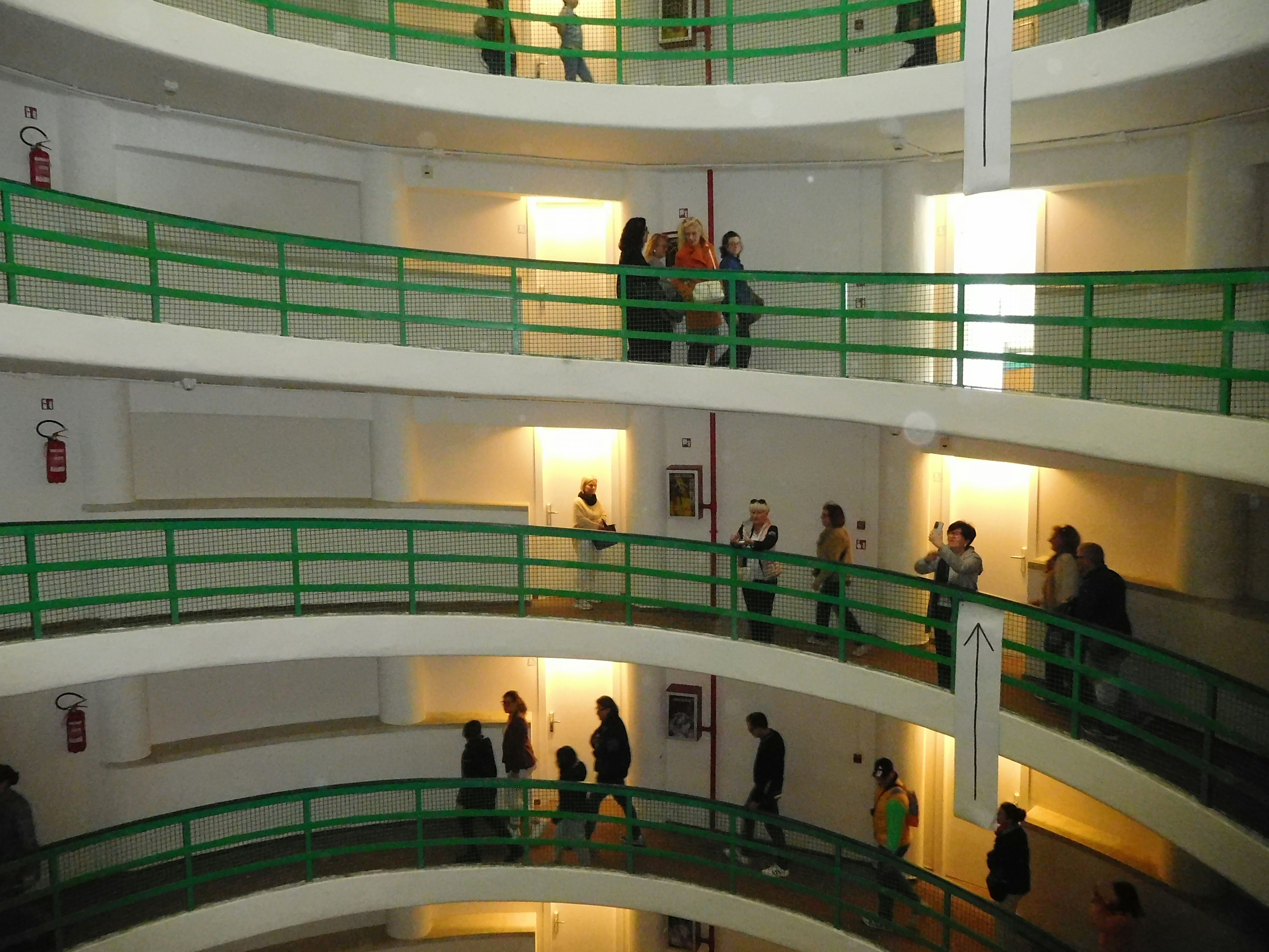 Circuits of Light: People and Green Railings in a Spiral Atrium