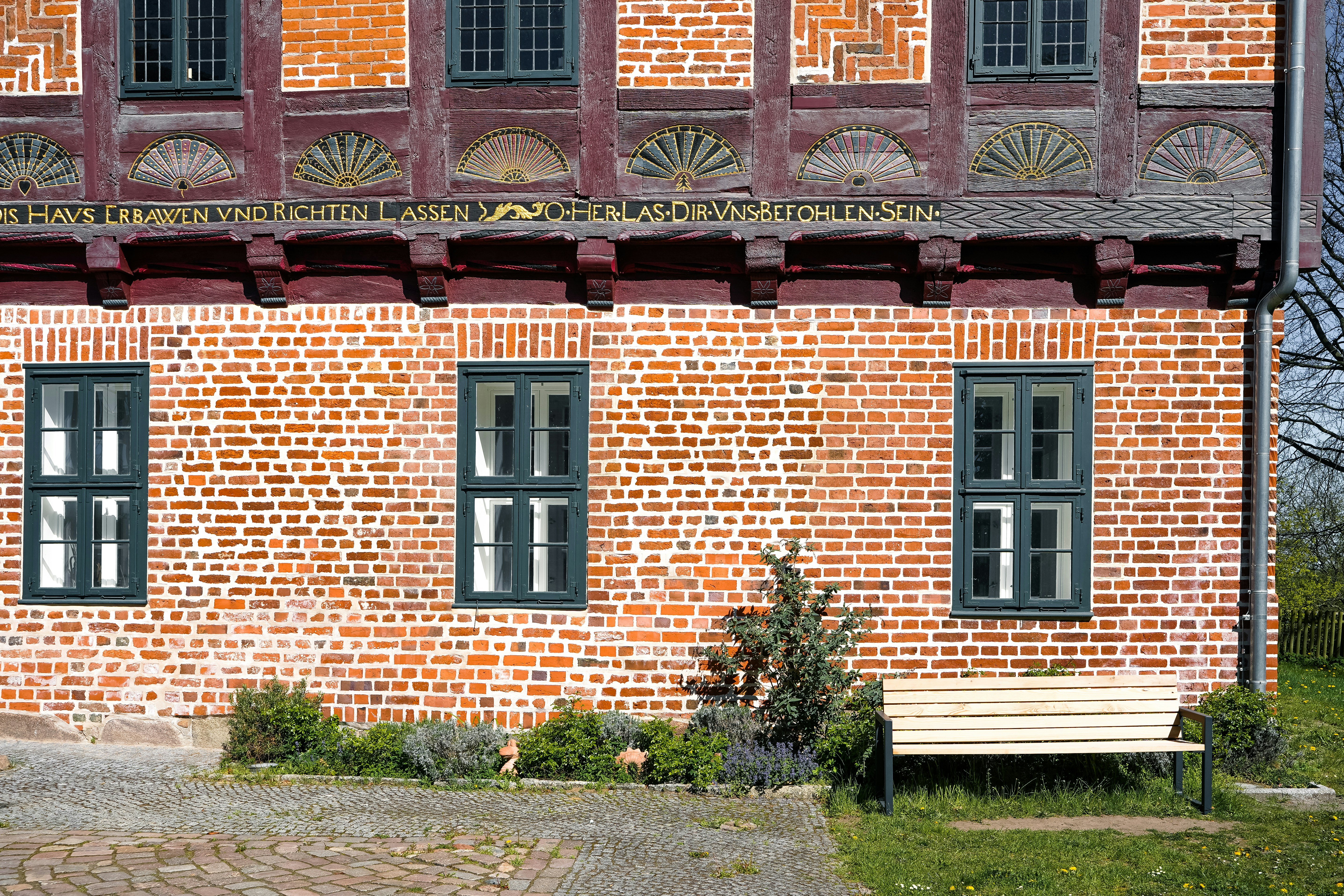 Brick Facade Portrait: Windows, Veranda, and a Quiet Park Bench