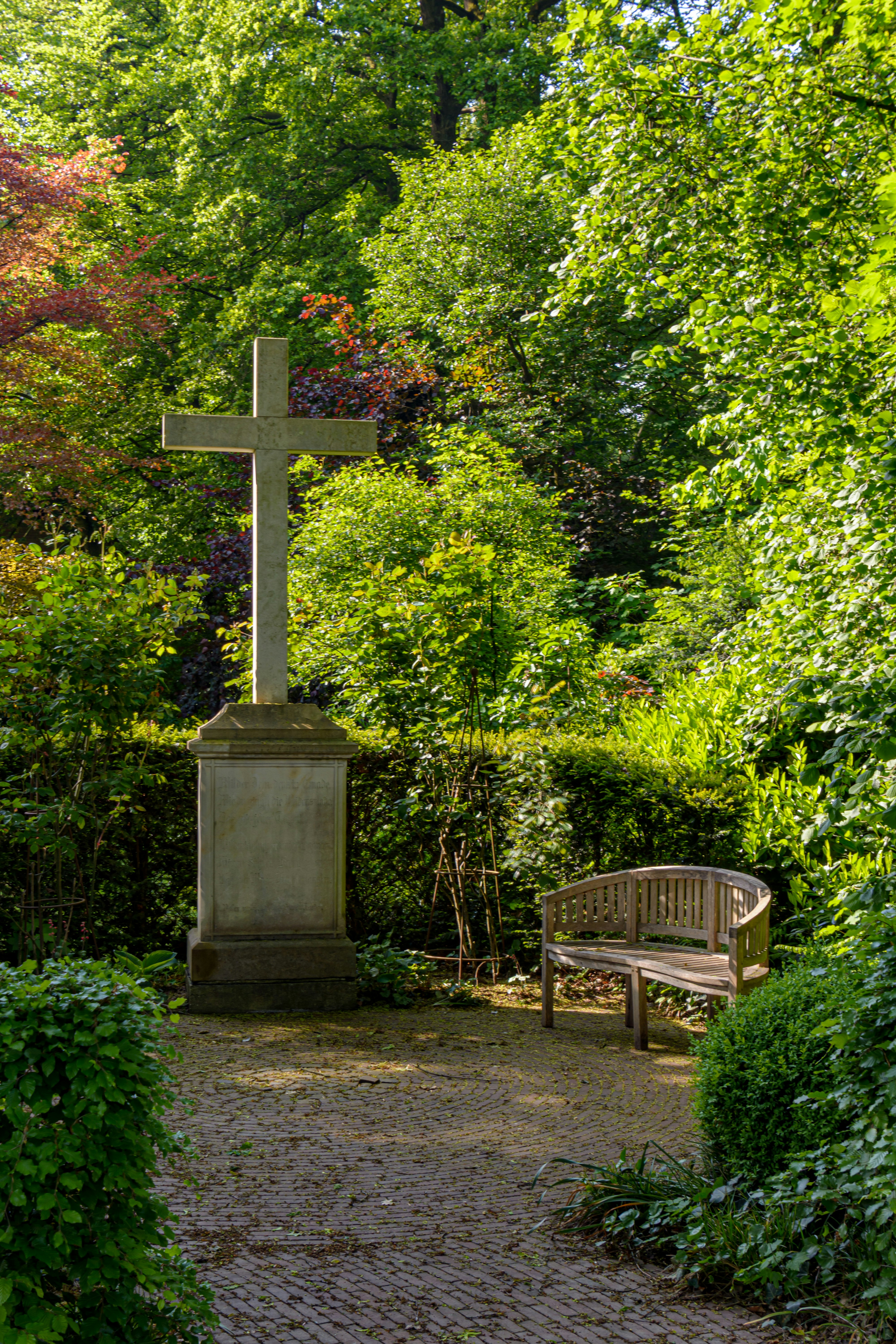 Silent Garden Memorial: A Bronze Cross Guarded by Greenery