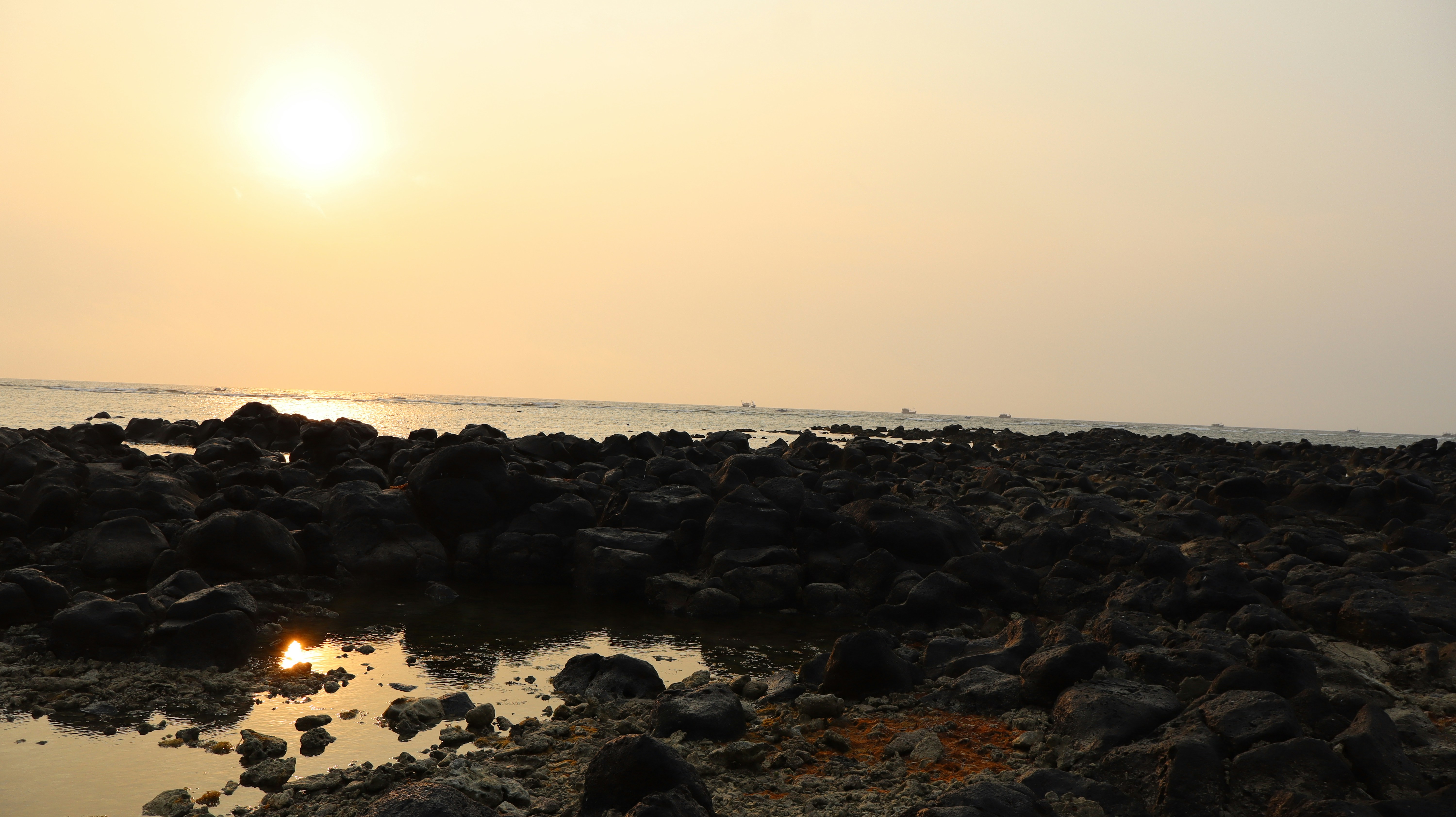 Horizon Quiet: Sunlit Shoreline Over Tumbled Rocks