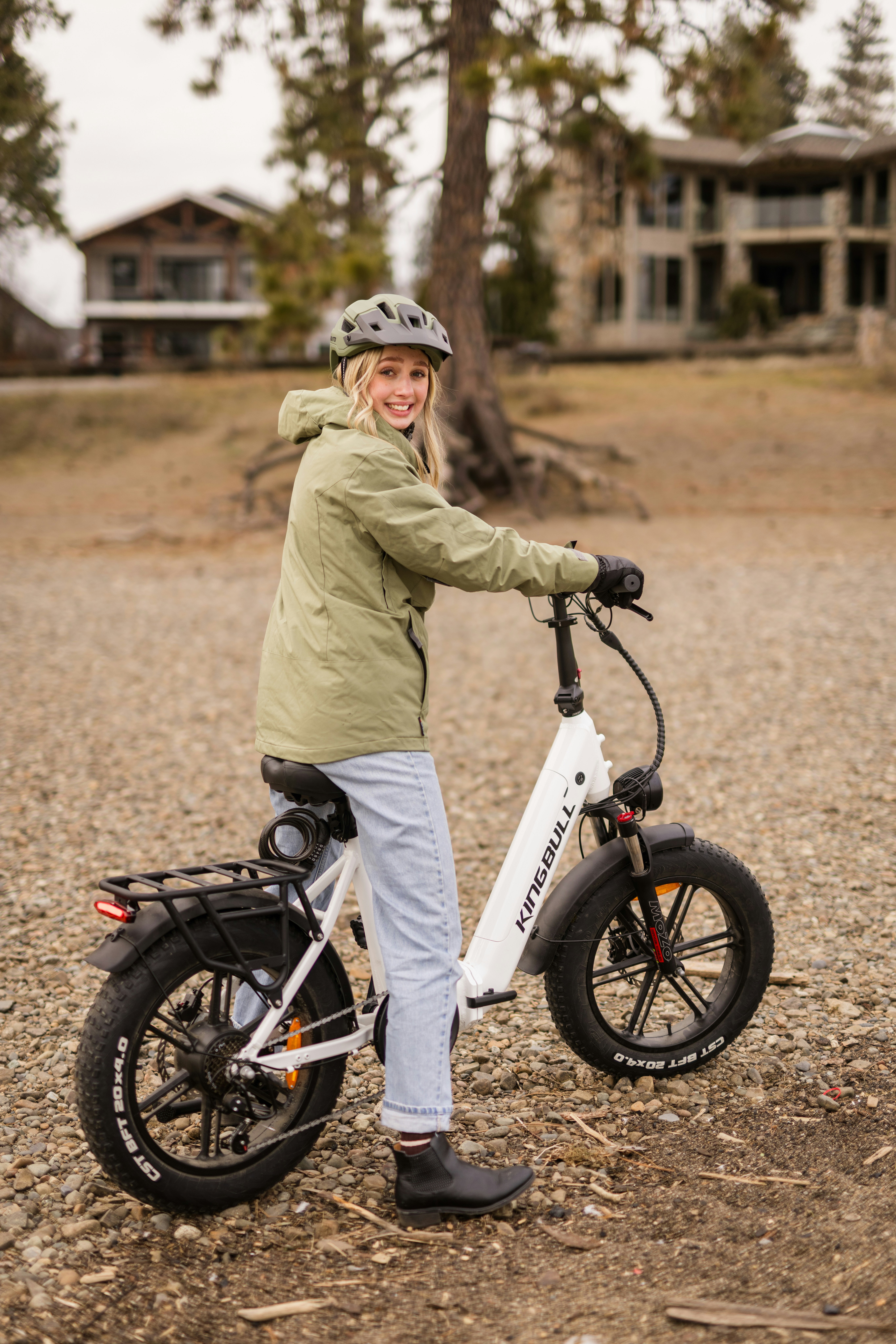  rider in olive jacket with helmet on an electric bike at lakeside camp
